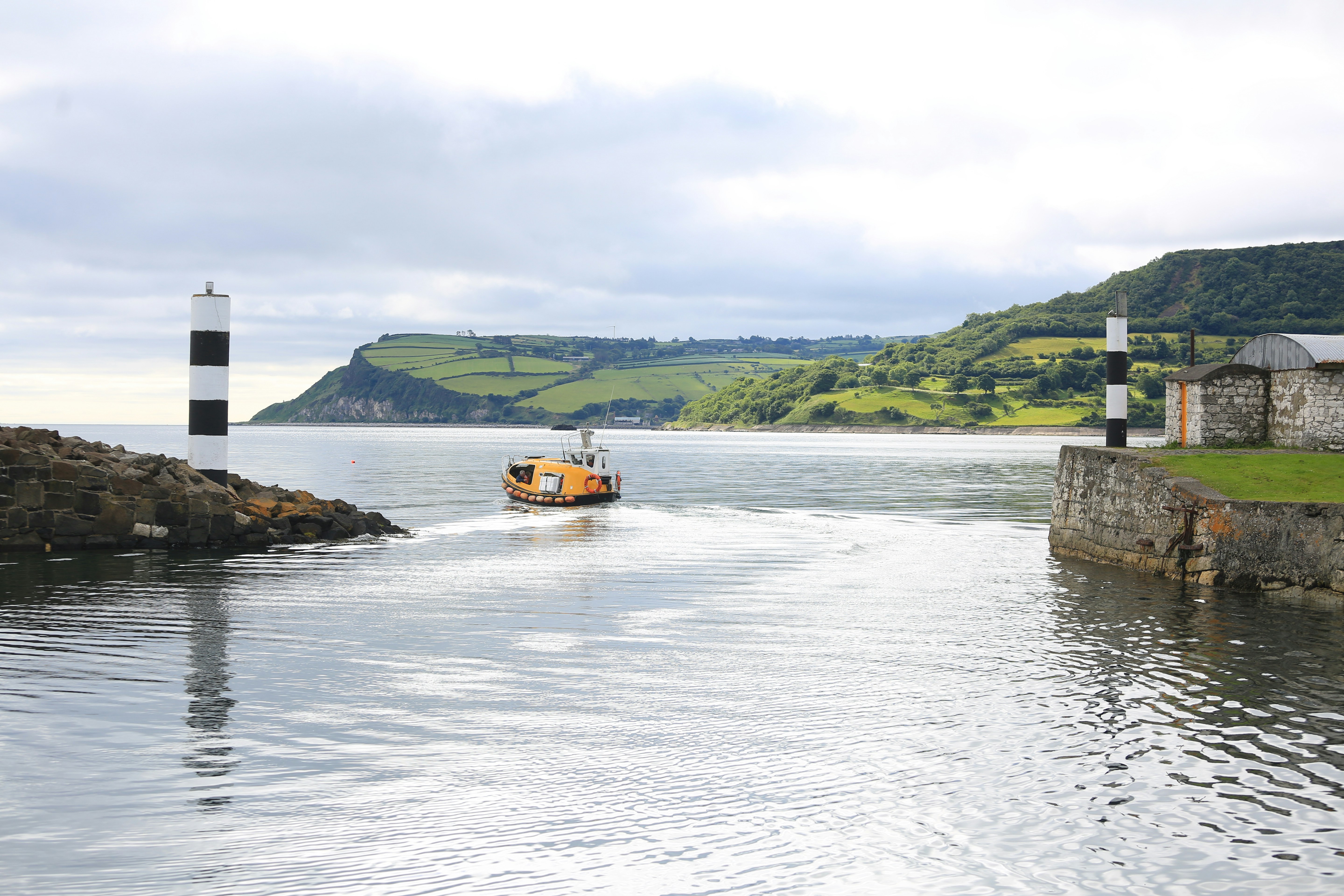 Yellow Boat in a Quiet Harbour Between Striped Pylons