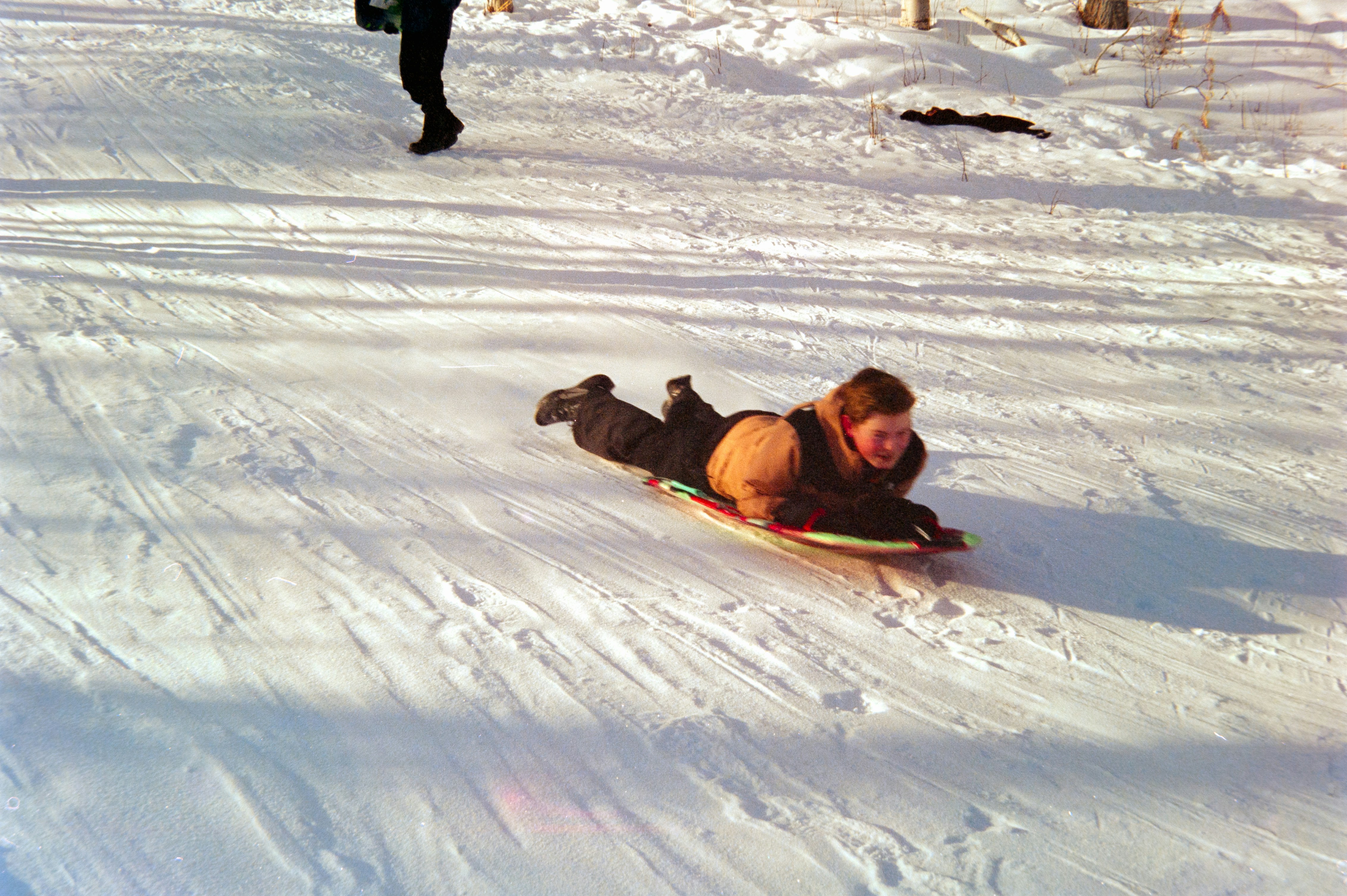 Snowbound Sprint: A Child Zips Down the Slope on a Wooden Sled