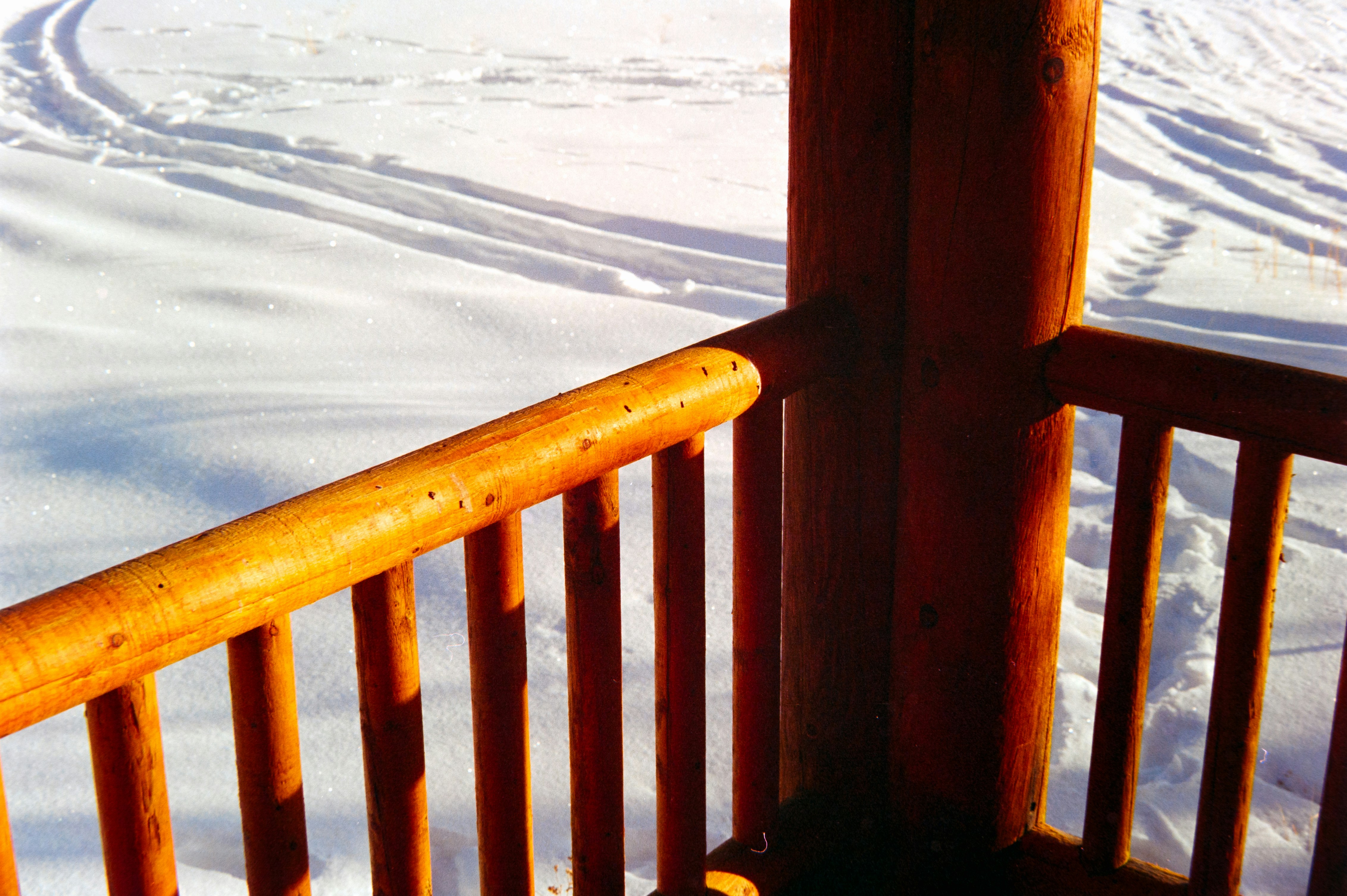 Sunlit Cedar Railings Framing a Quiet Snowfield