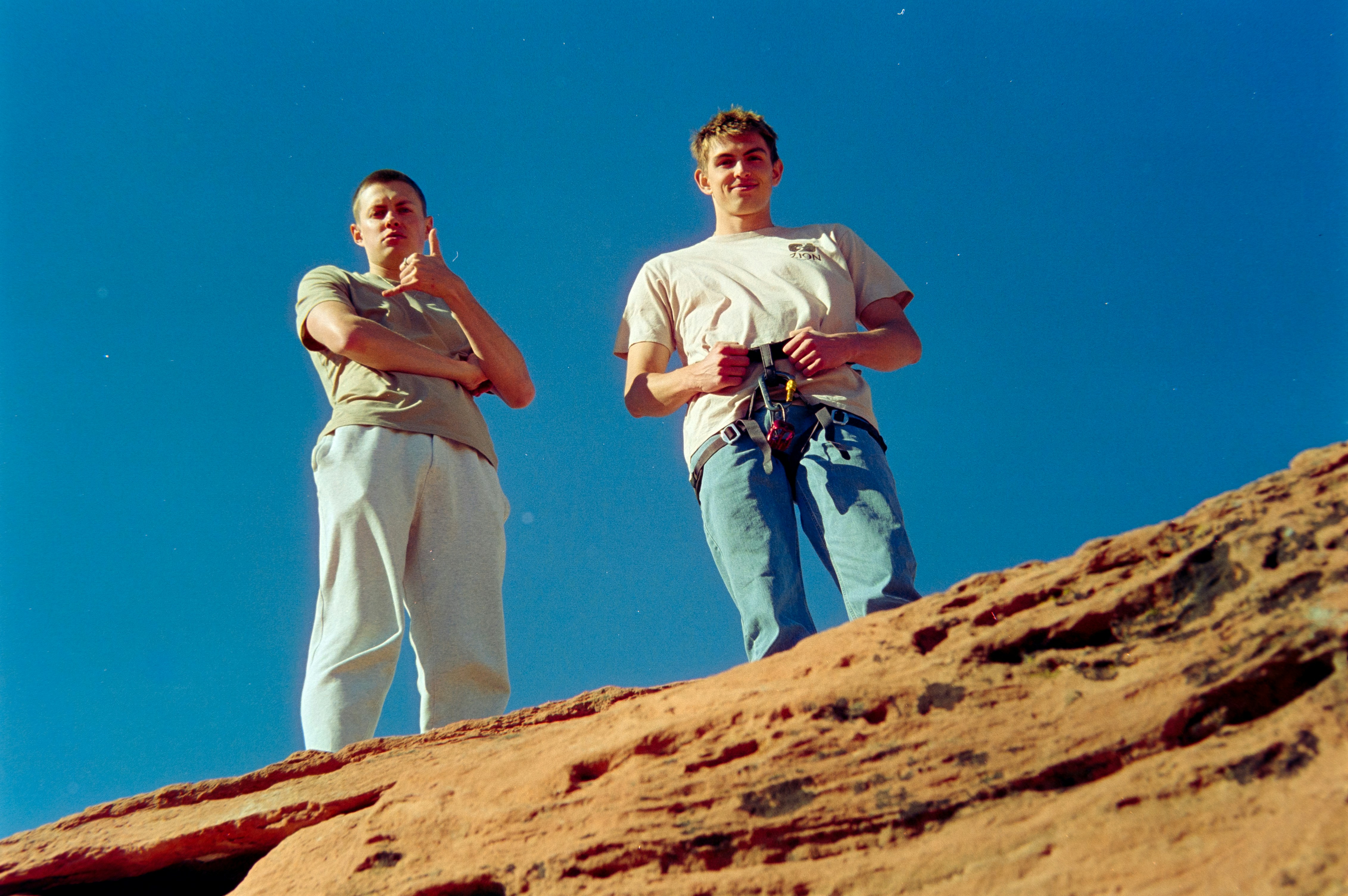 Two Figures Atop Red Ridge Under Deliberate Blue