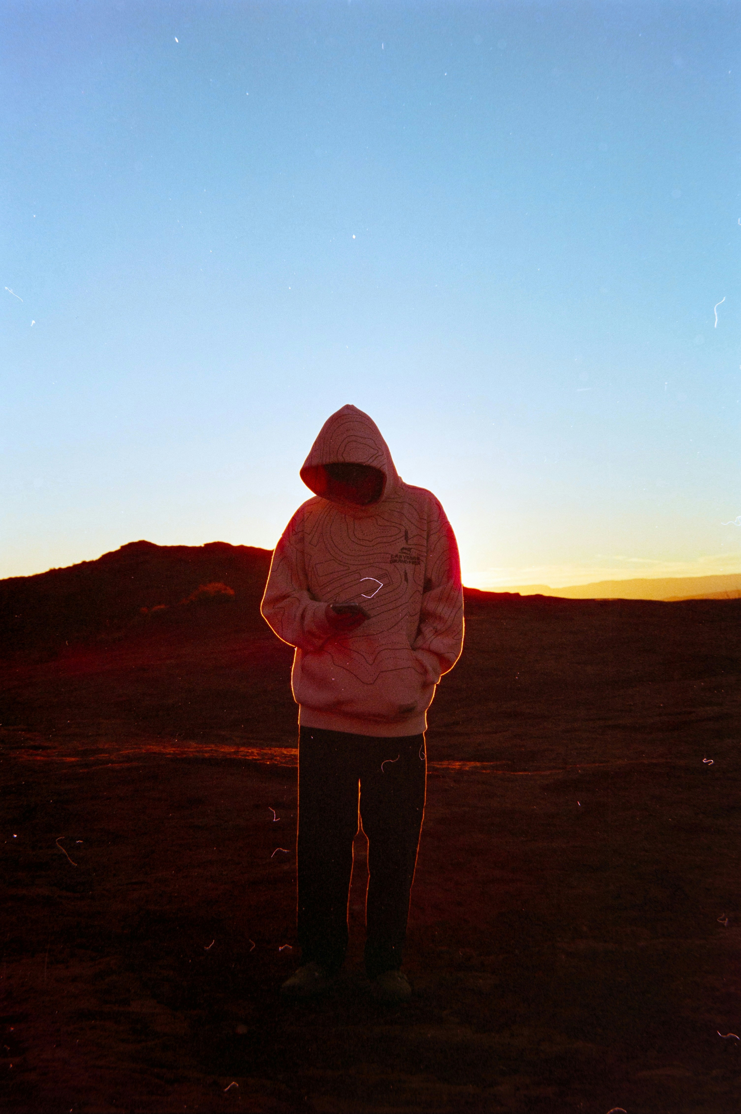 Hooded Figure at Dusk: Red Rim Light on a Desert Horizon