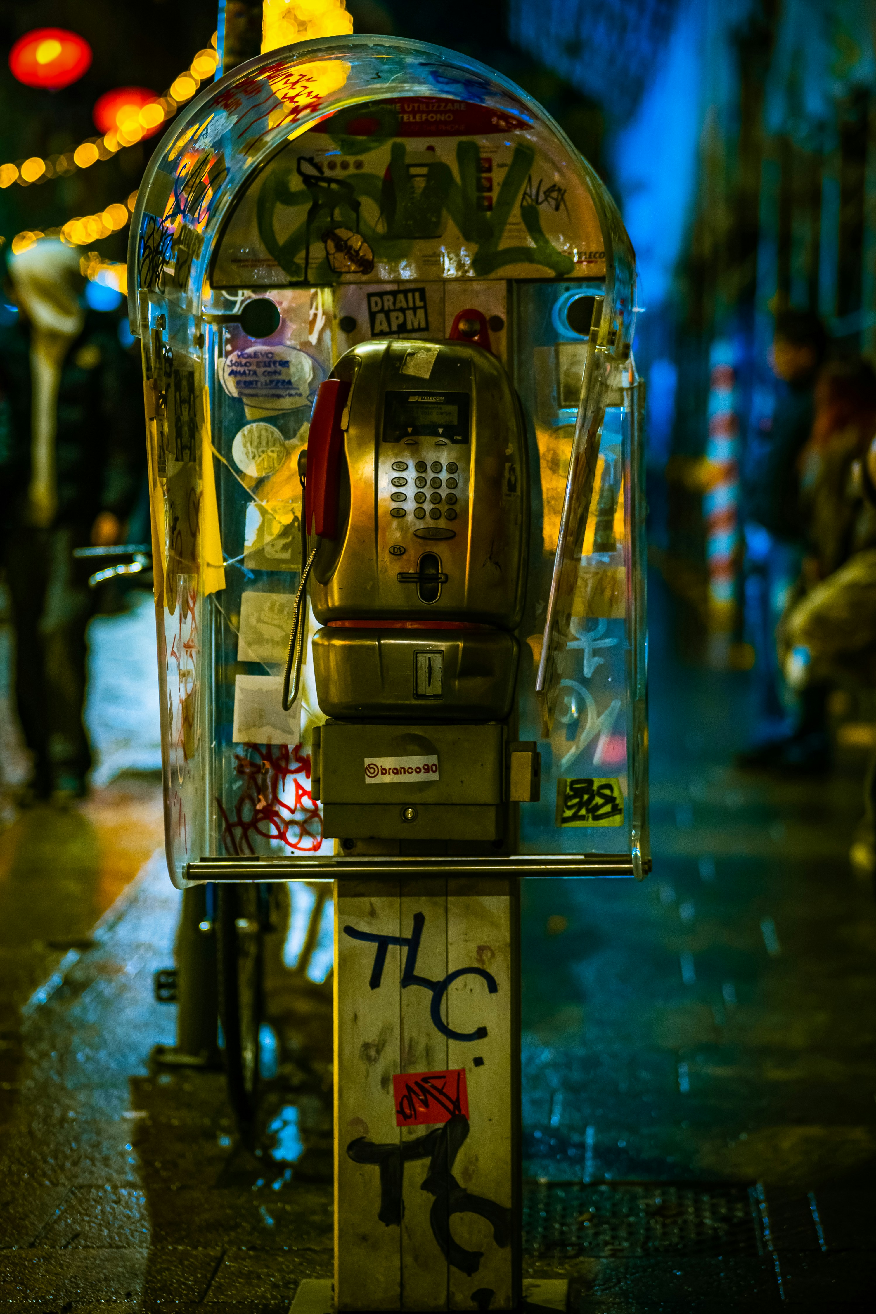 Neon Telephone Booth: A Rain-Slick Night Amid Street Graffiti