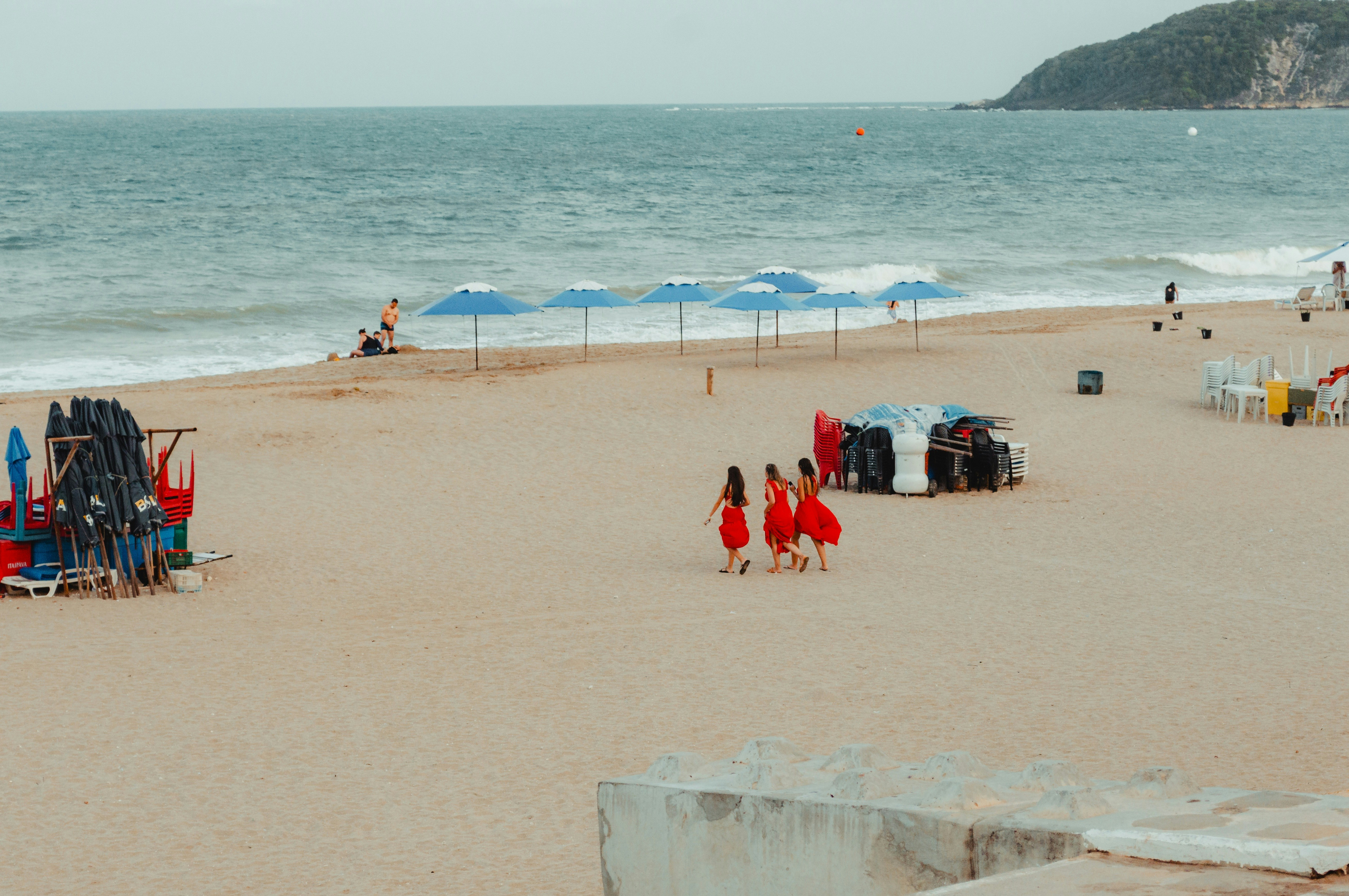 Three Red-dressed Tourists on a Calm Beach Rooftop of Sand