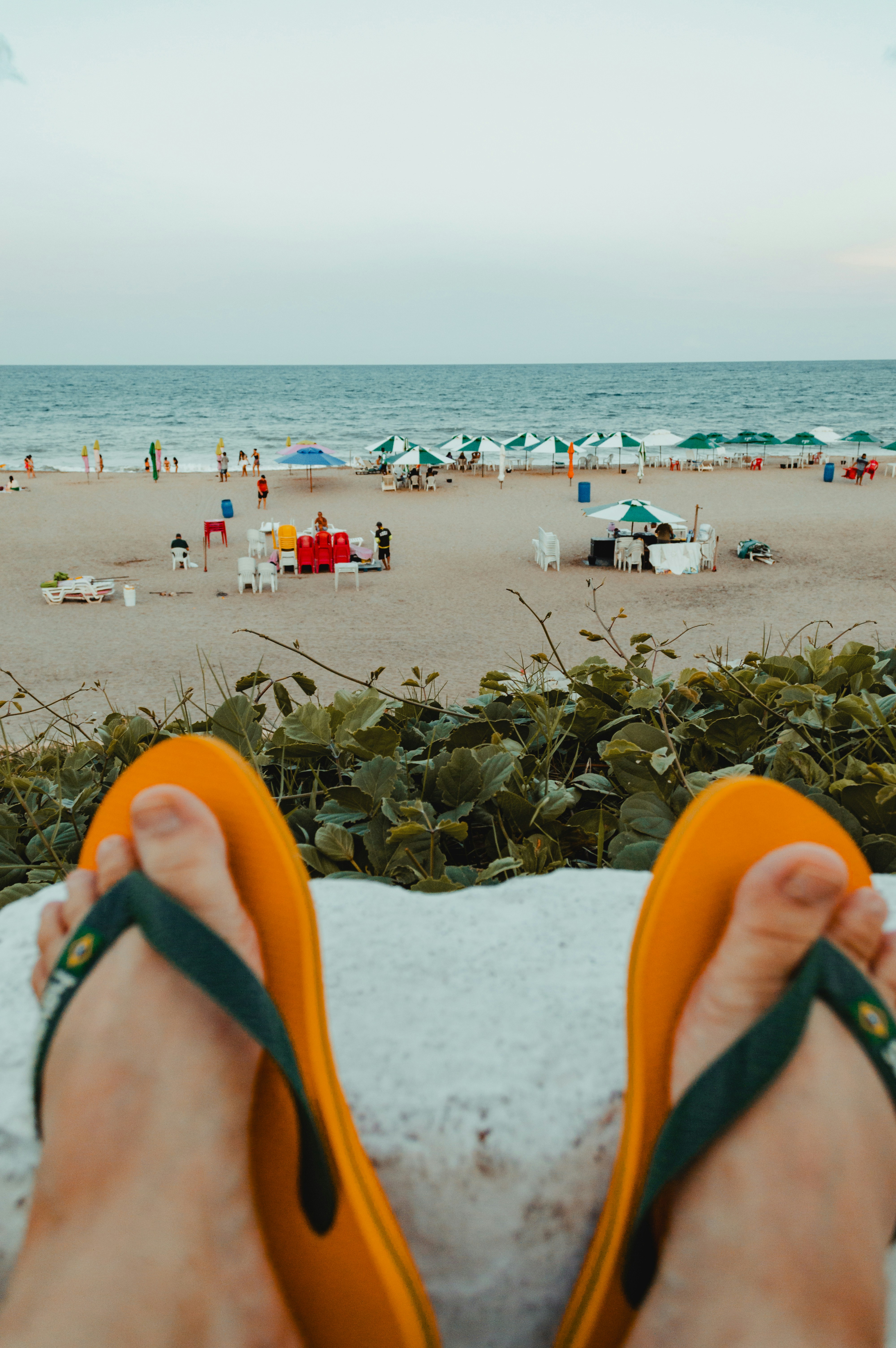 Orange Sandals Overlooking a Bustling Beach