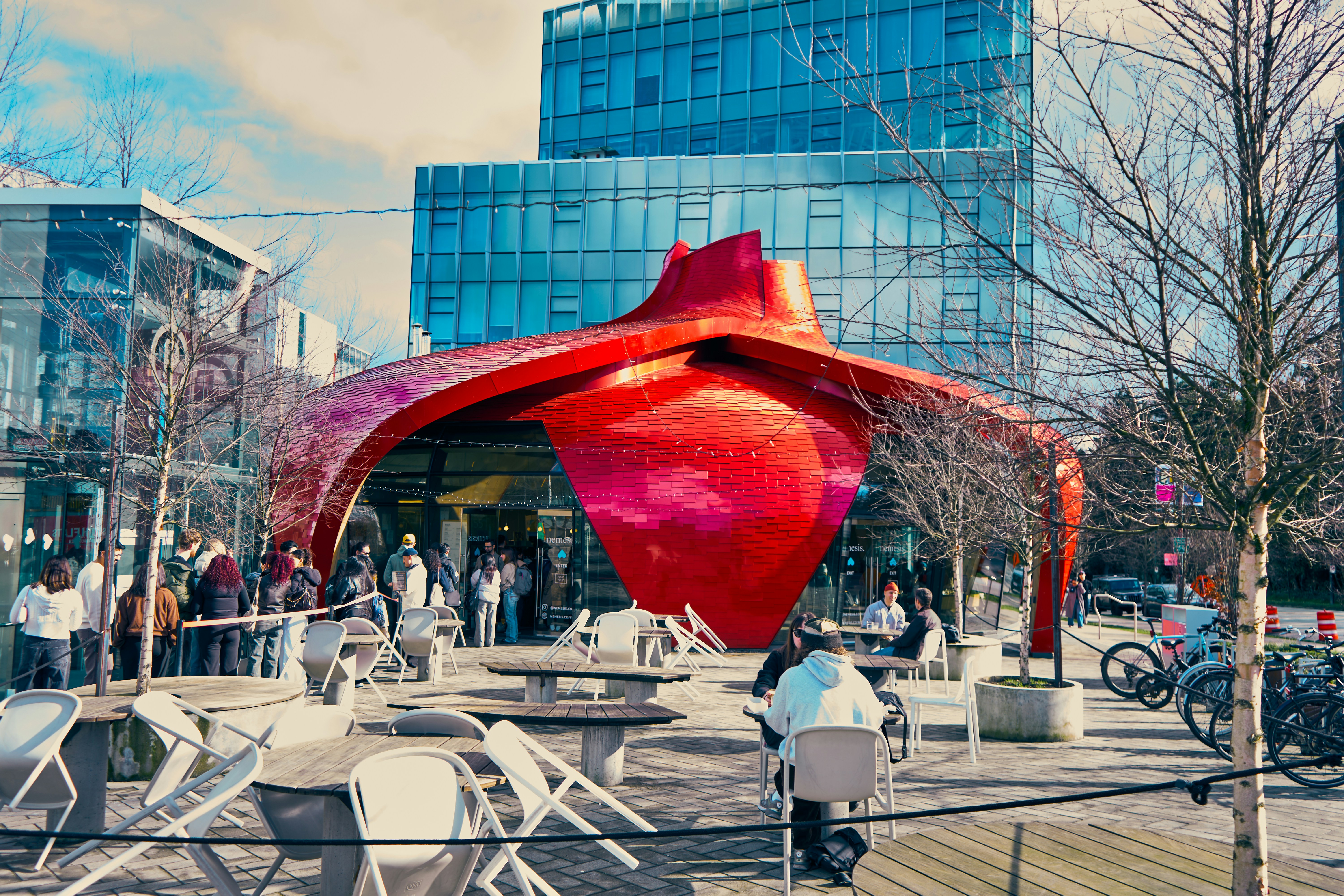 Red Shell of Social Heat: A Curved Sculpture in a Busy Outdoor Café