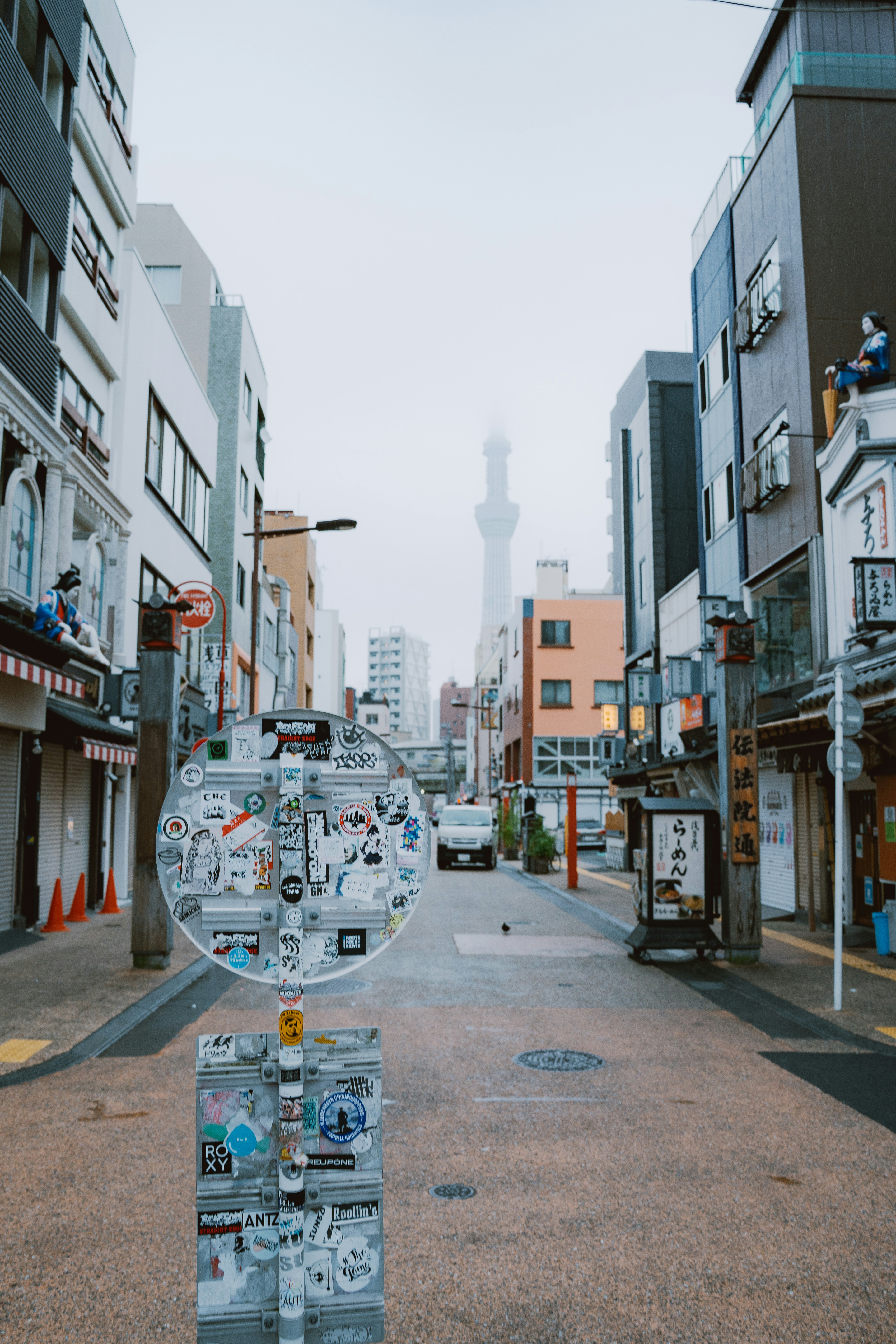 Stickered Circular Signpost in a Quiet Tokyo Street