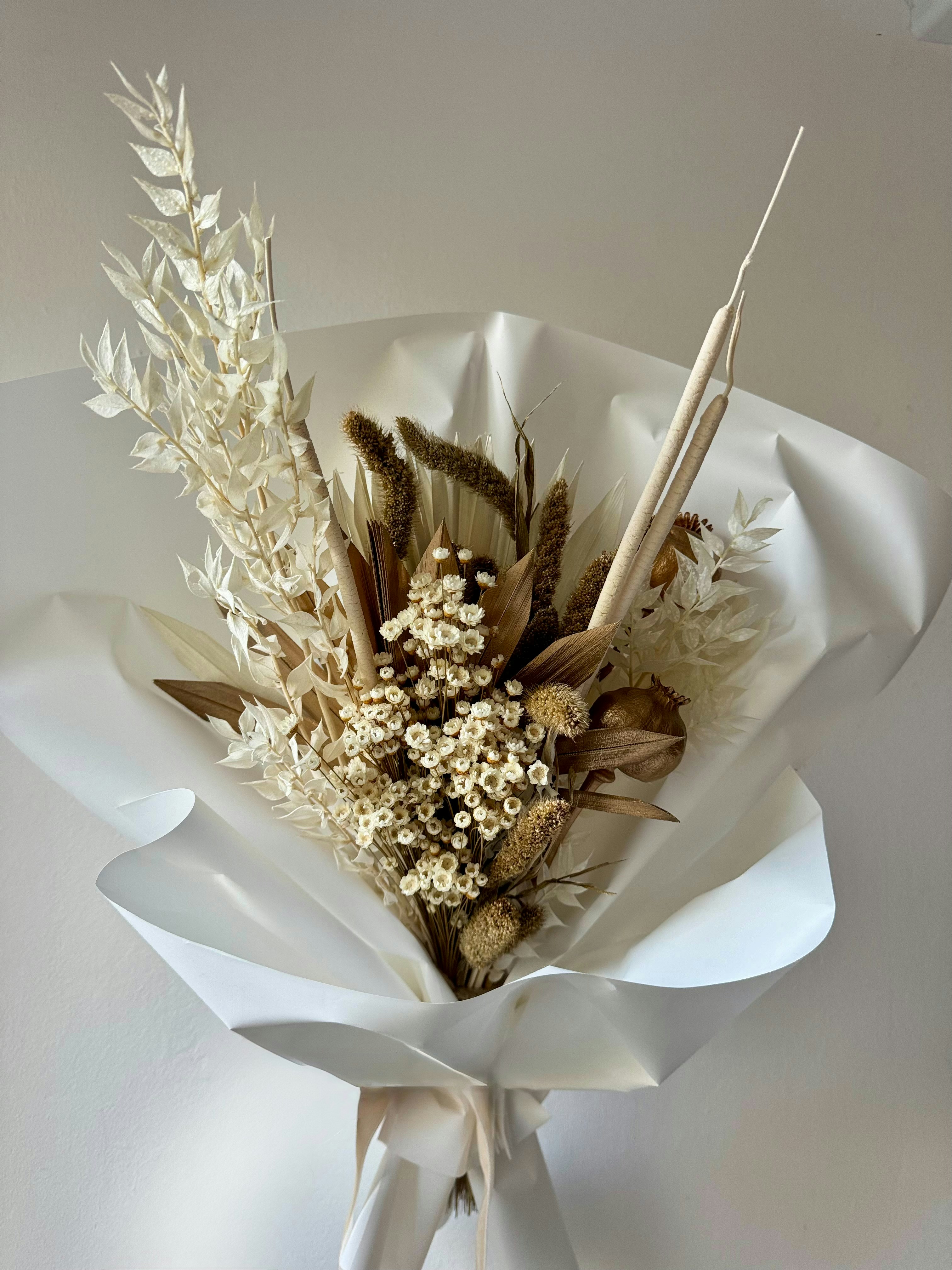 Minimalist dried bouquet in white wrapping with pale grain tones