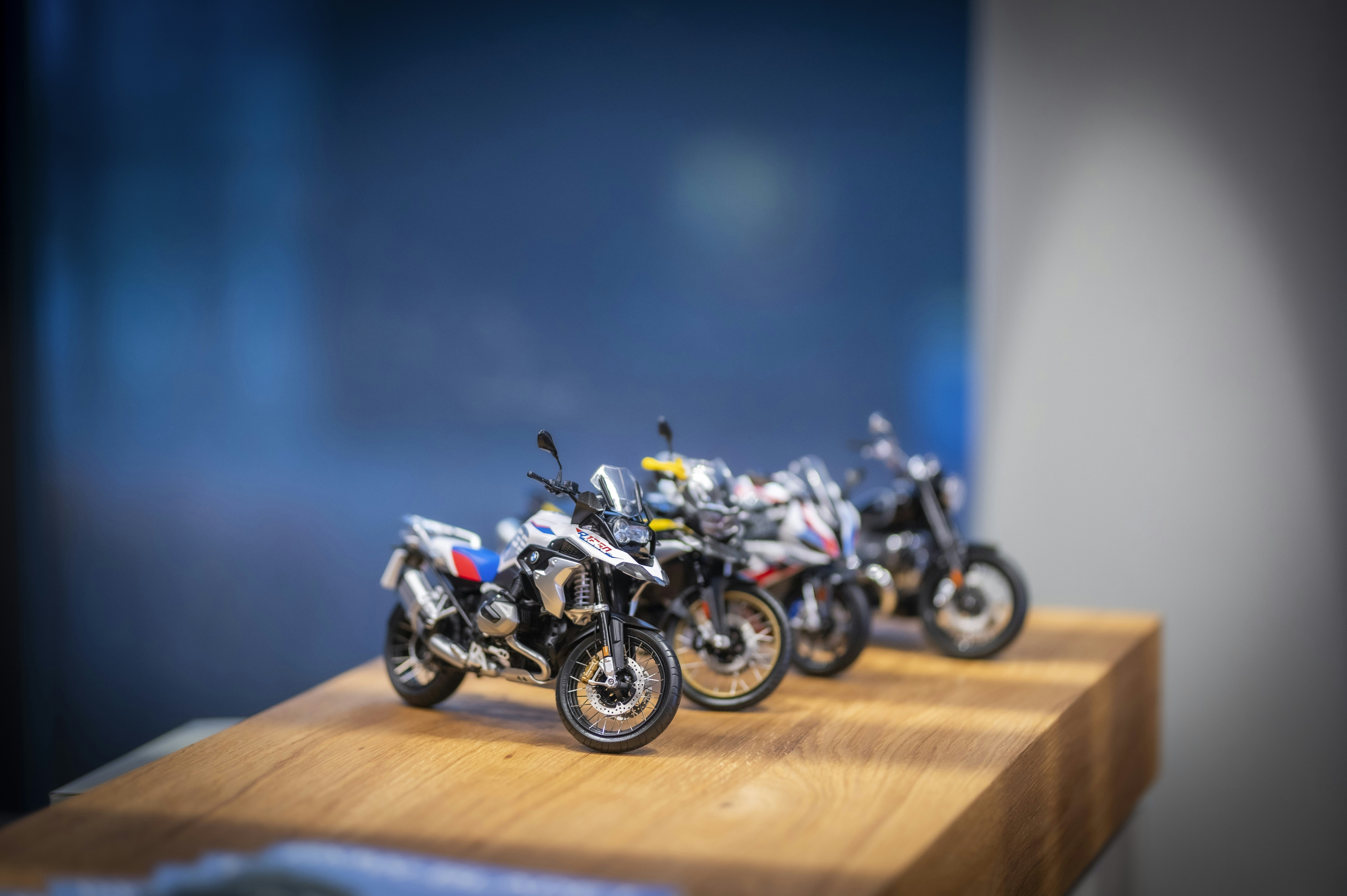 Tiny Thunder: A Row of Model Motorcycles on a Wooden Pedestal