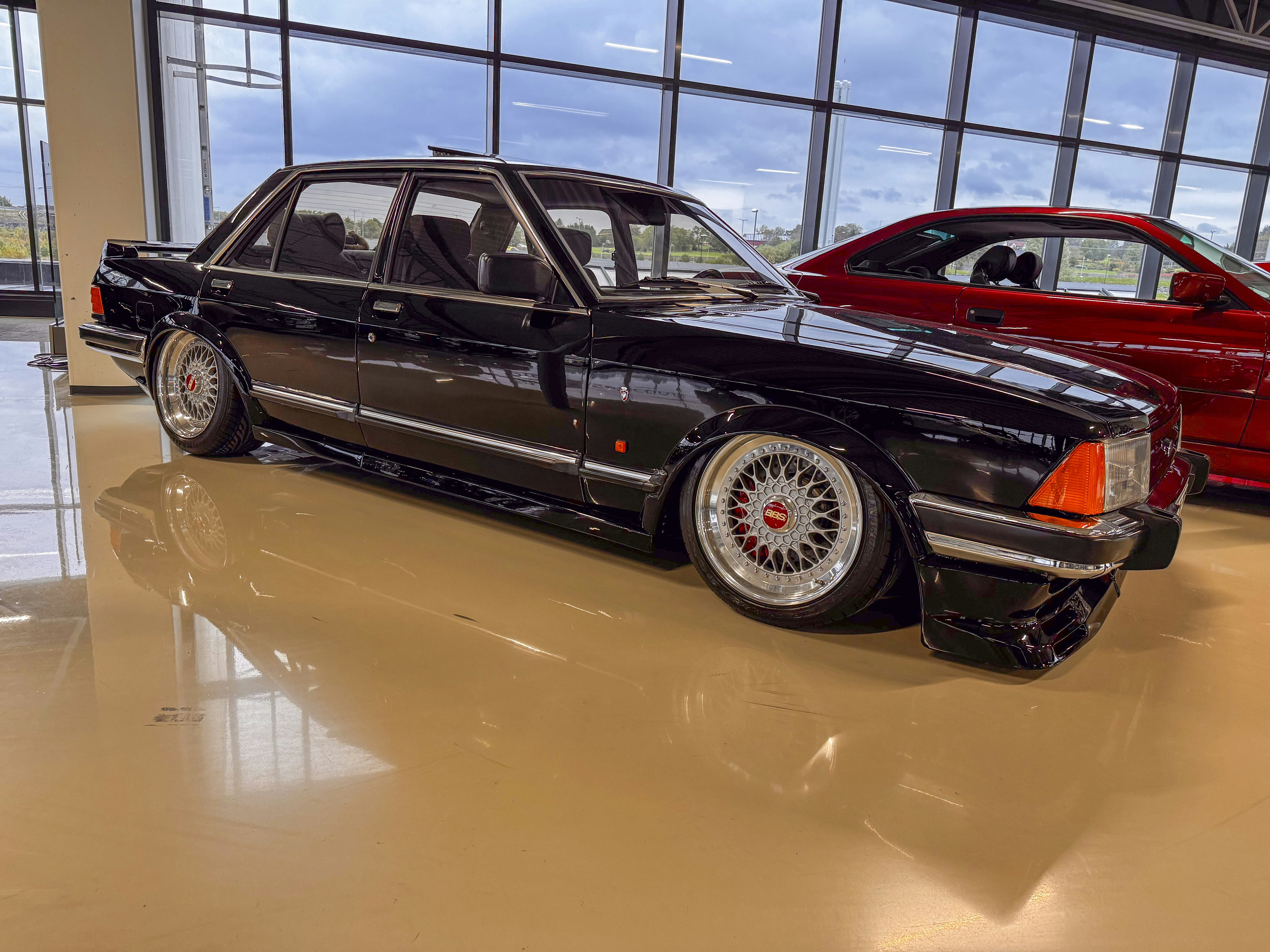 Black Luxury Sedan Amid Shiny Showroom Reflections