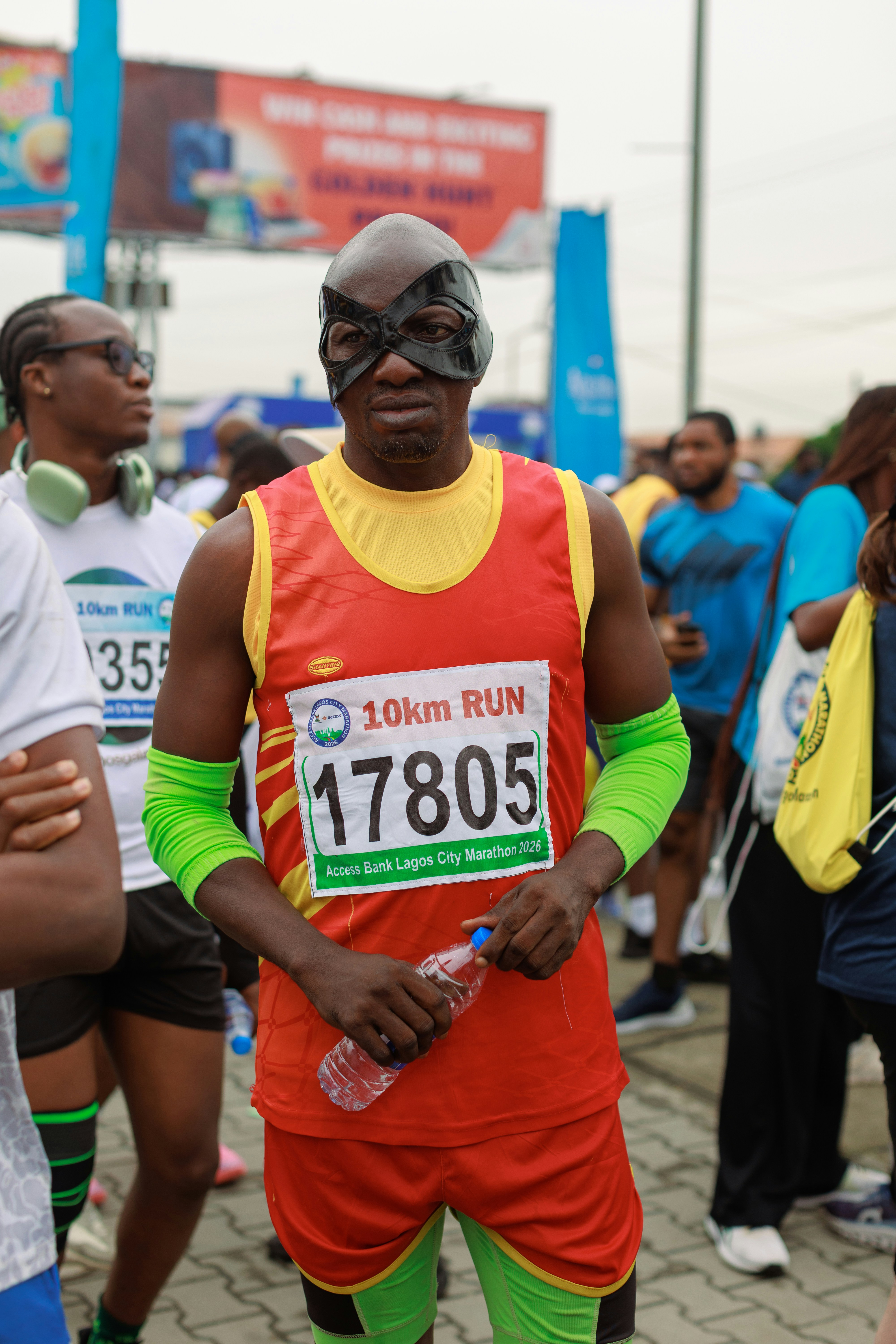 Marathoner in Bright Orange with Neon Green Gear at the Finish Crowd