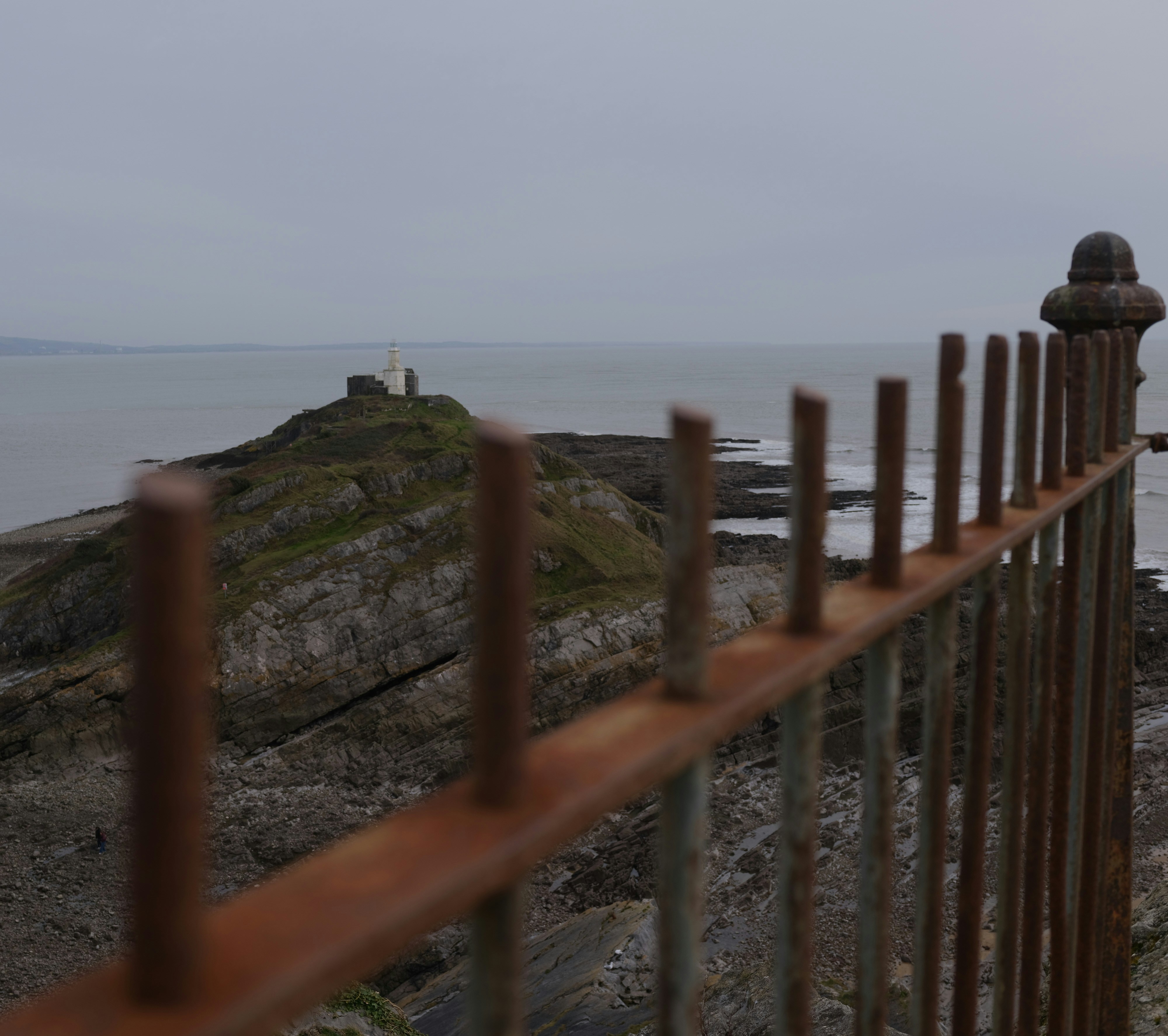 Rusted Rails Over a Quiet Sea: A Lighthouse at the End of the Breakwater