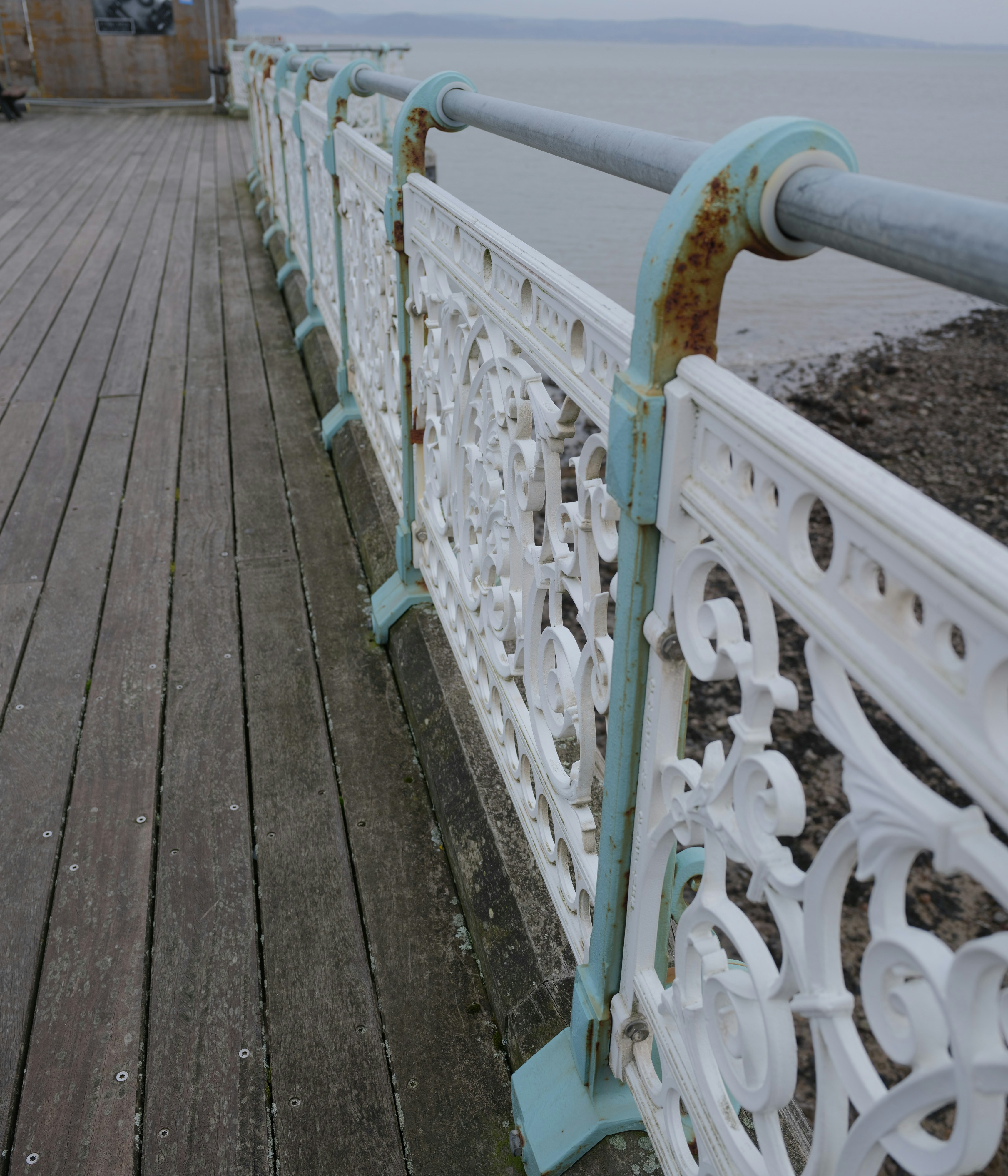 Rusted railing and weathered planks along a seaside promenade