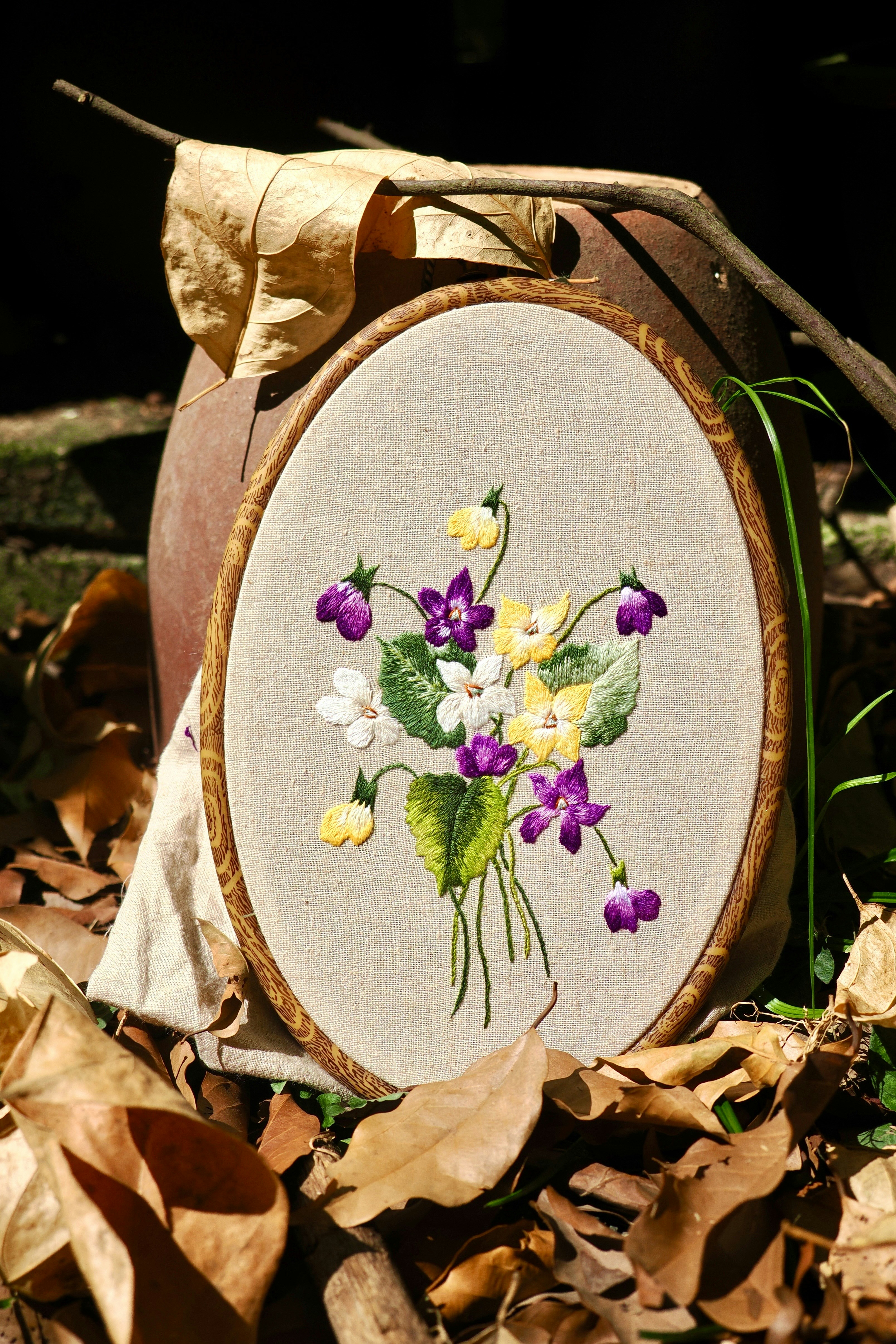 Embroidered Bouquet Within a Vintage Hoop, Surrounded by Autumn Leaves
