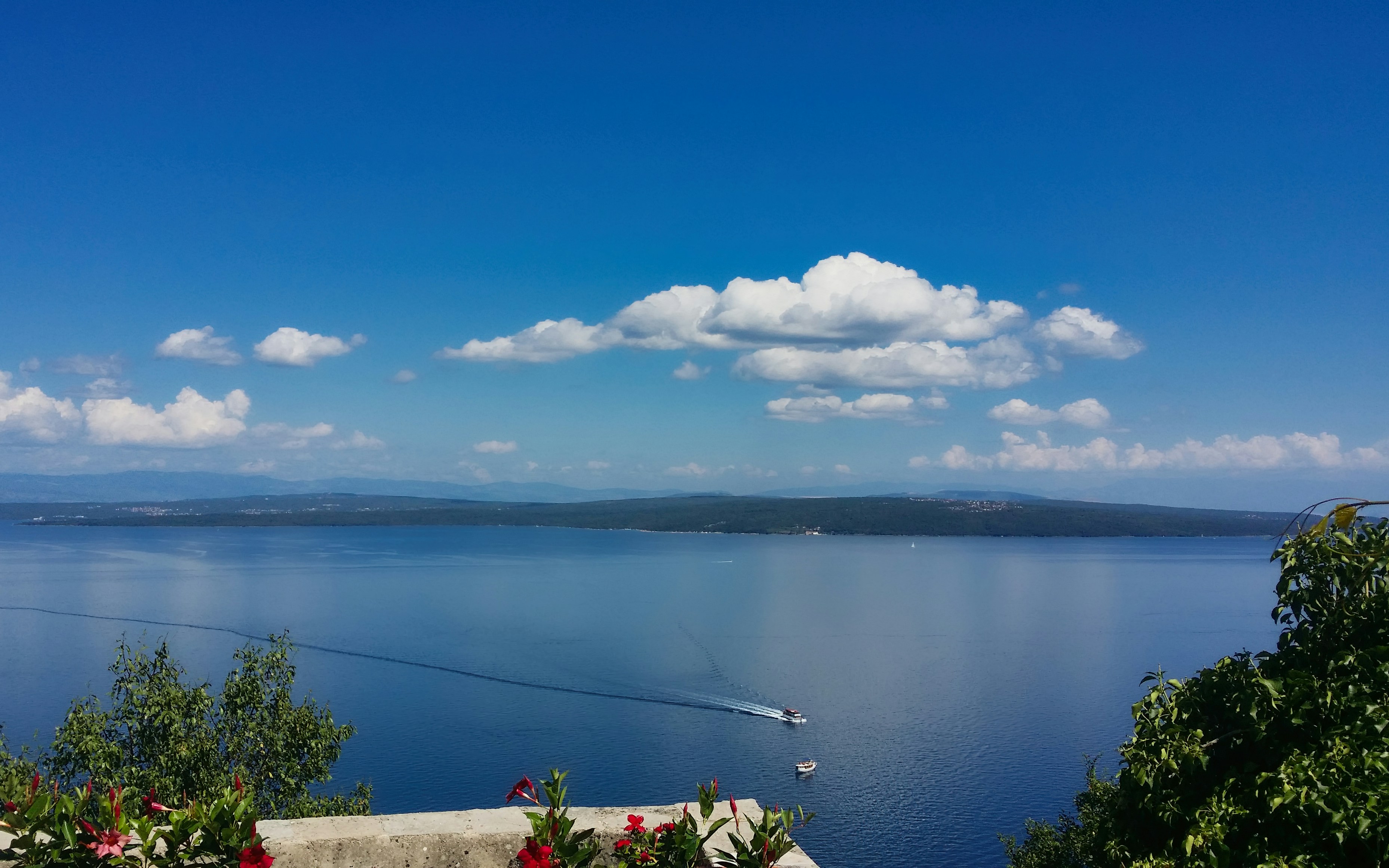 Calm blue sea with distant islands and fluffy clouds.
