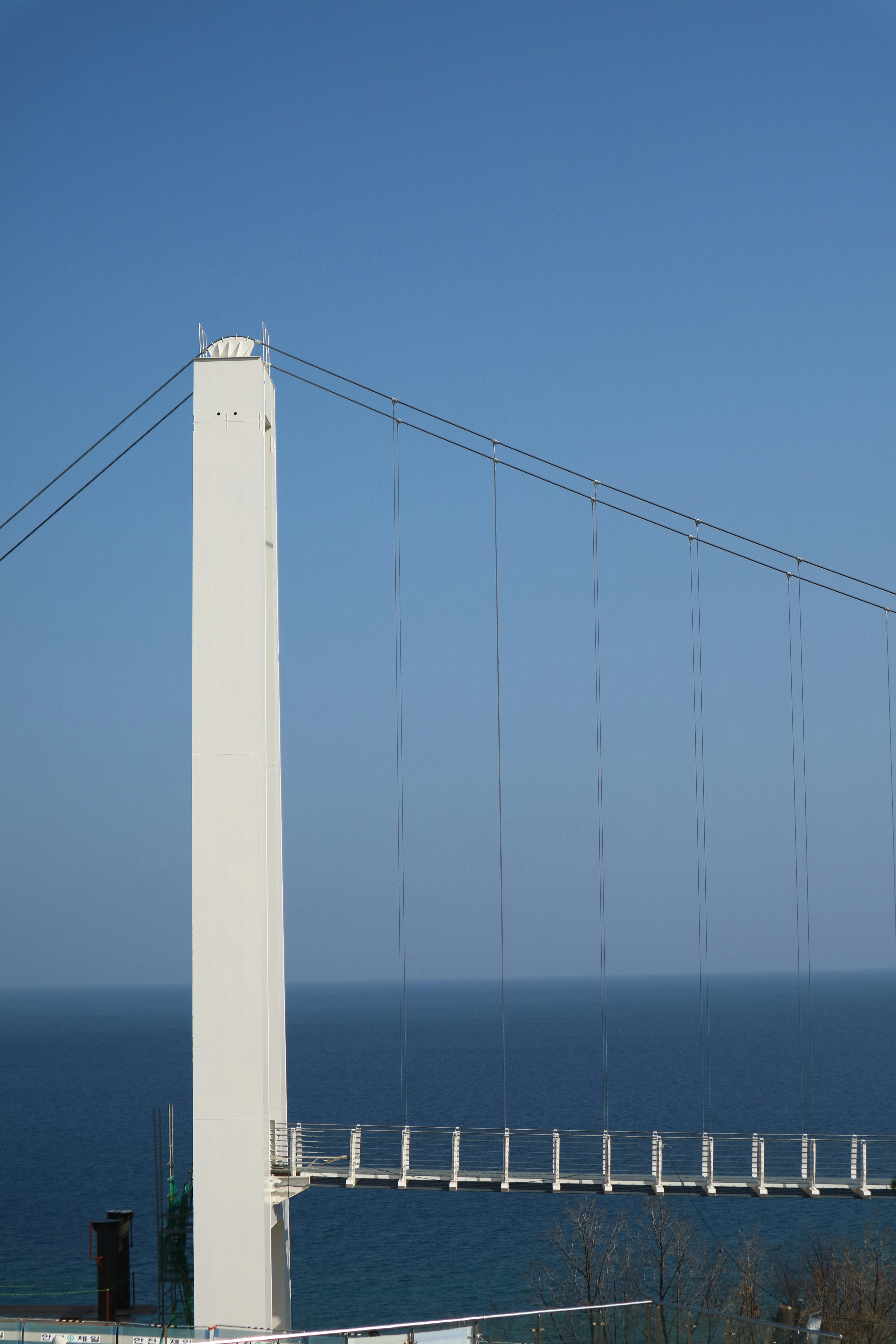 White tower and suspension cables over a blue sea
