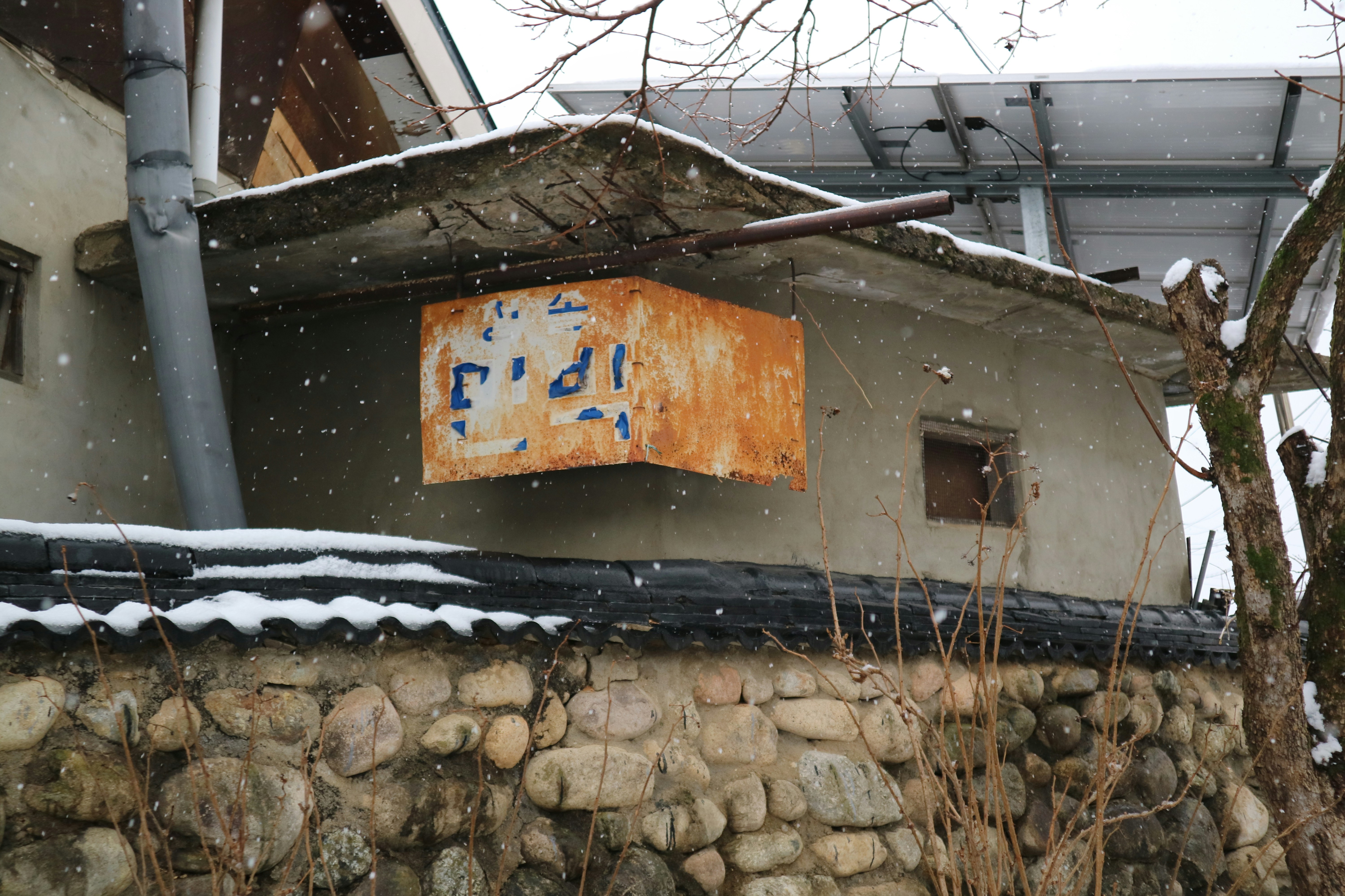 Weathered Signpost Over A Snow-Crowned Stone Wall