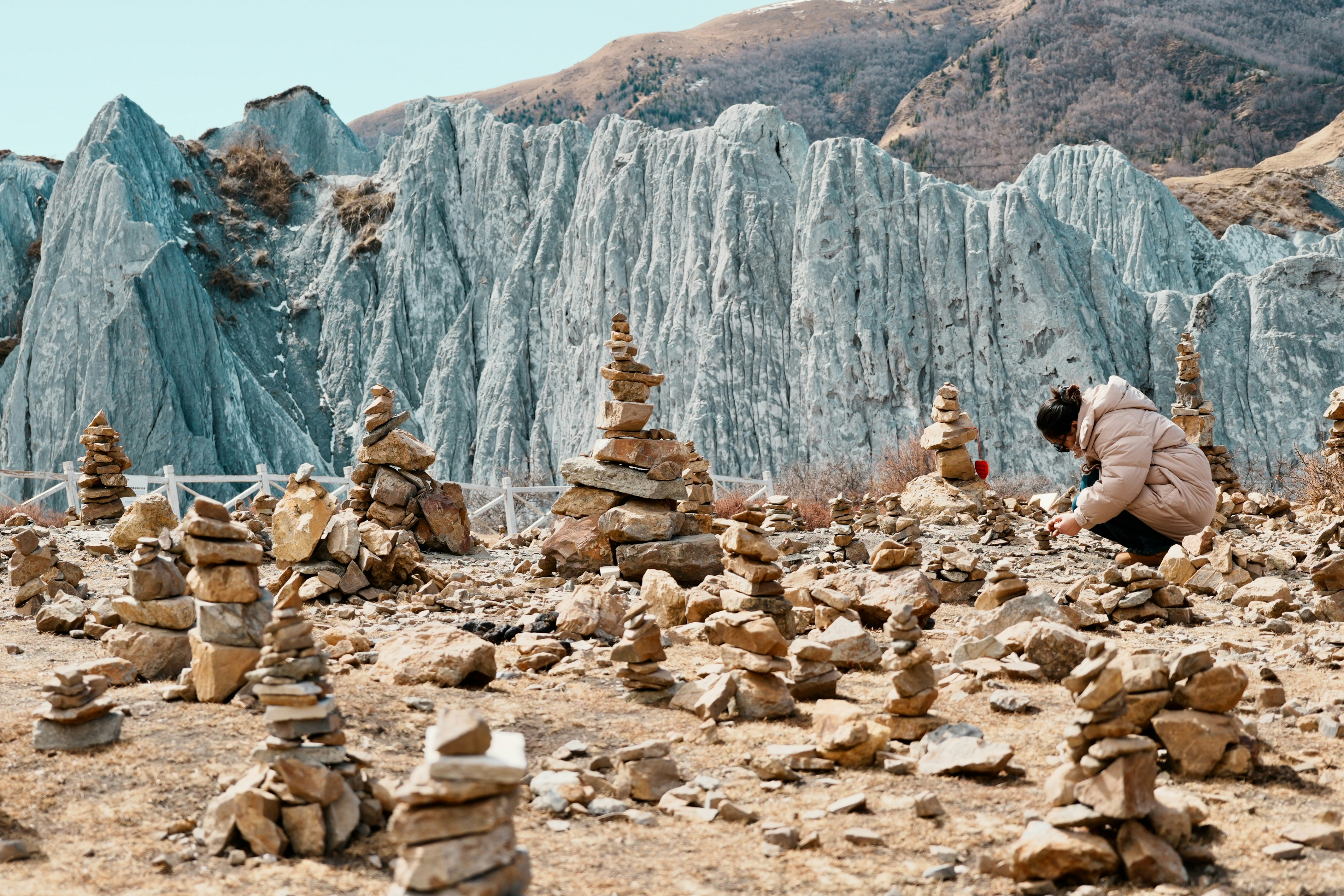 Stone Cairns and a Distant Climber beneath Jagged Glass Formations