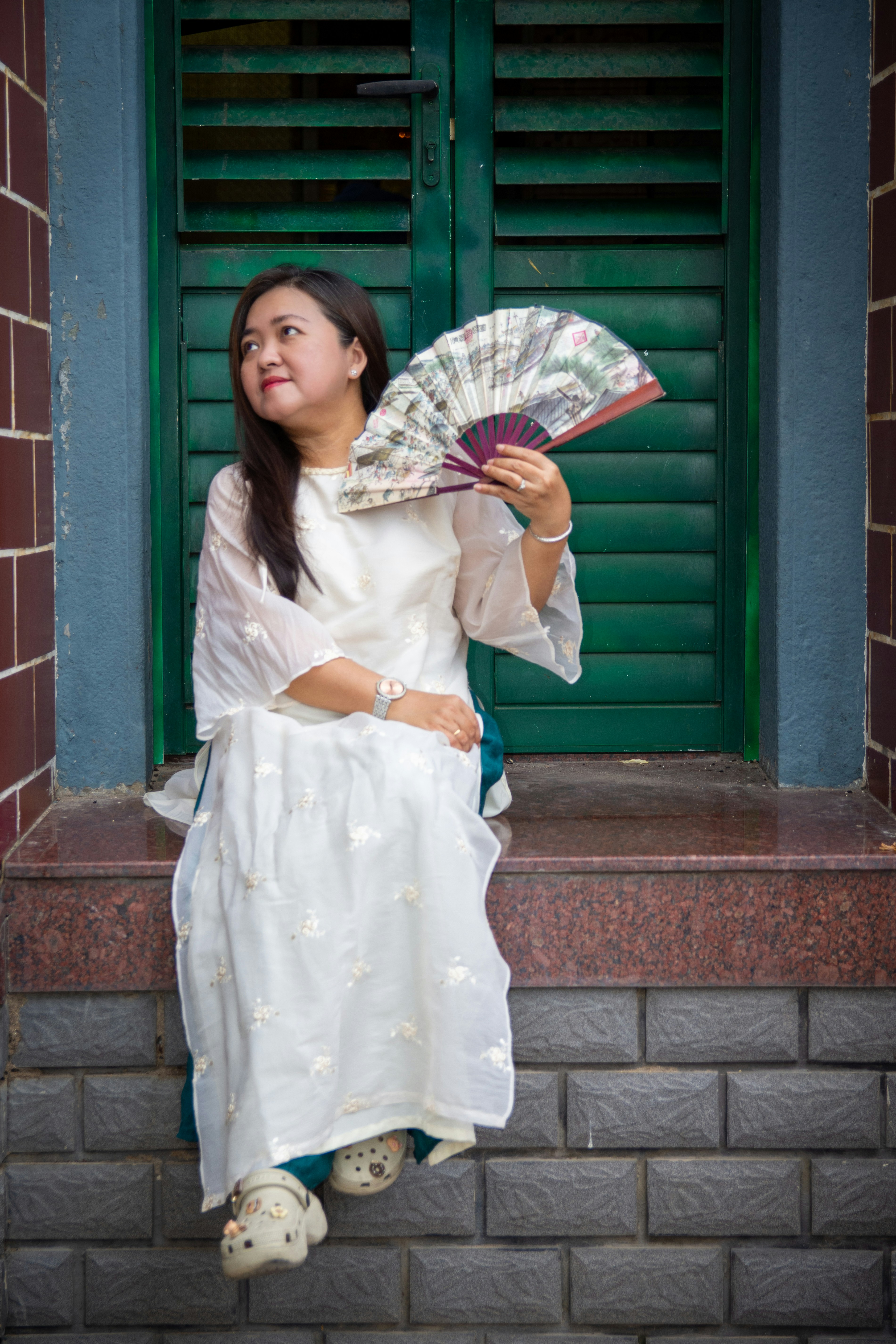 Elegance on the Steps: A Quiet Moment with a Fan