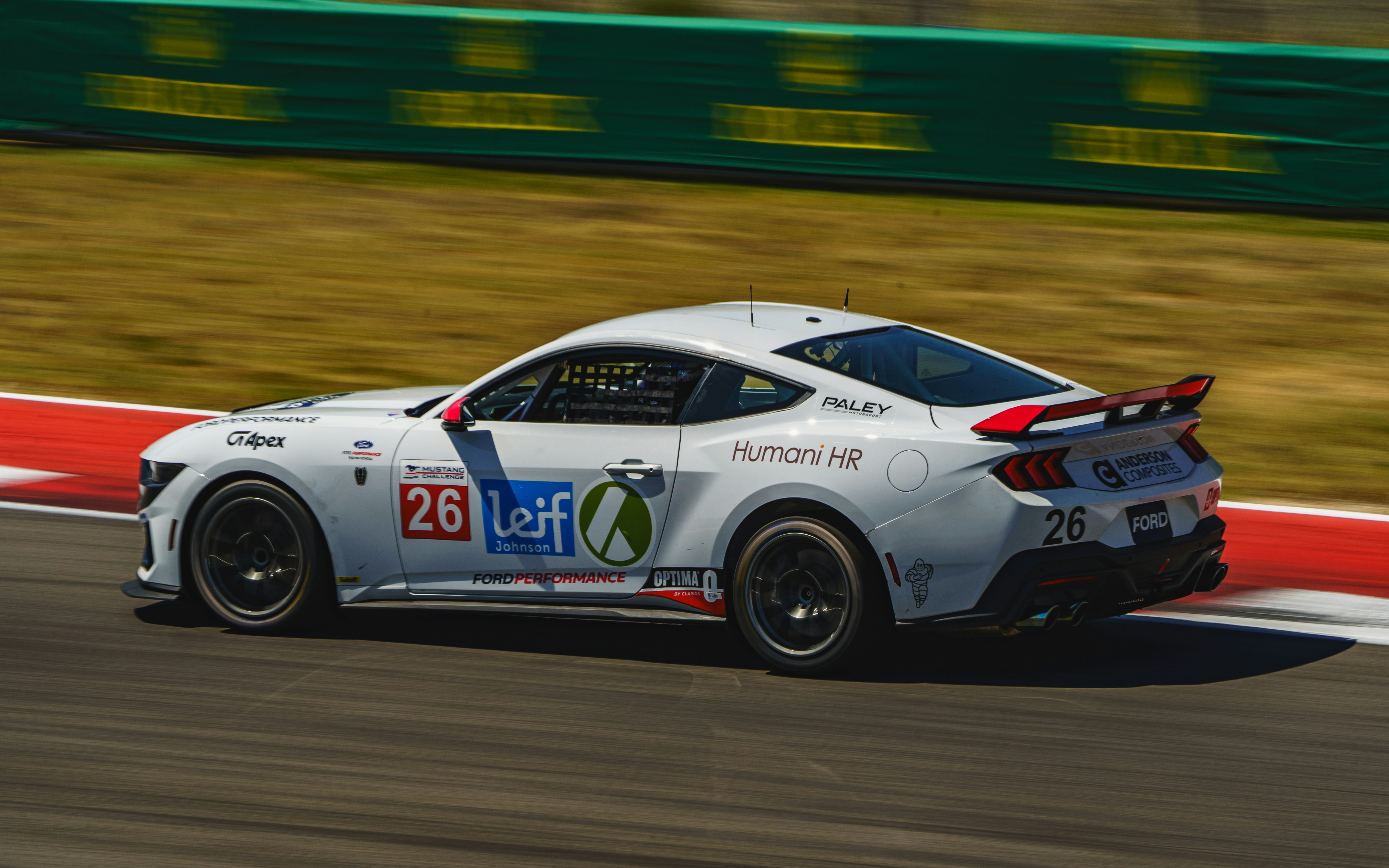 Racing silhouette: white GT car cracks the curb in motion