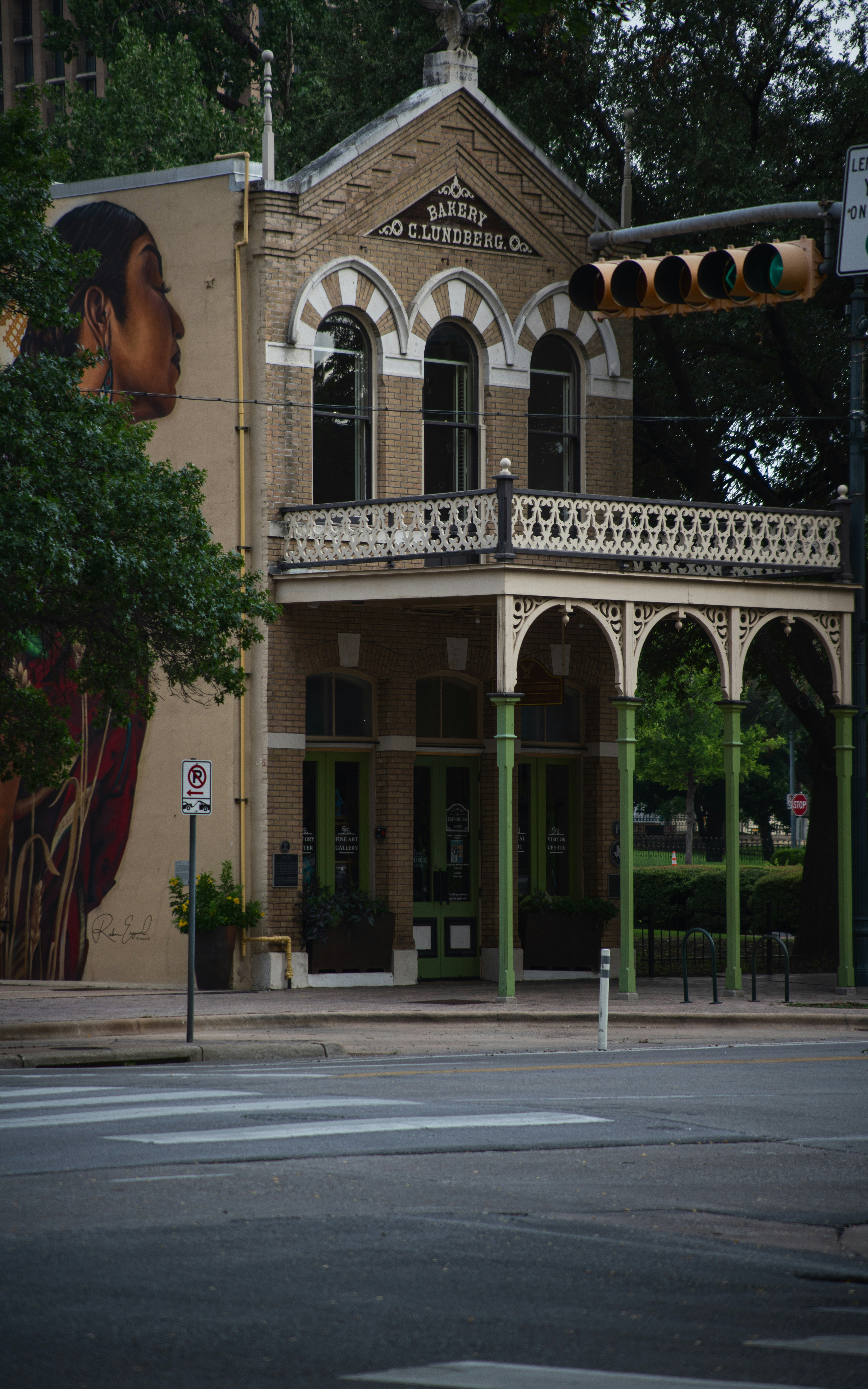 Historic storefront with ornate balcony and mural in a quiet street