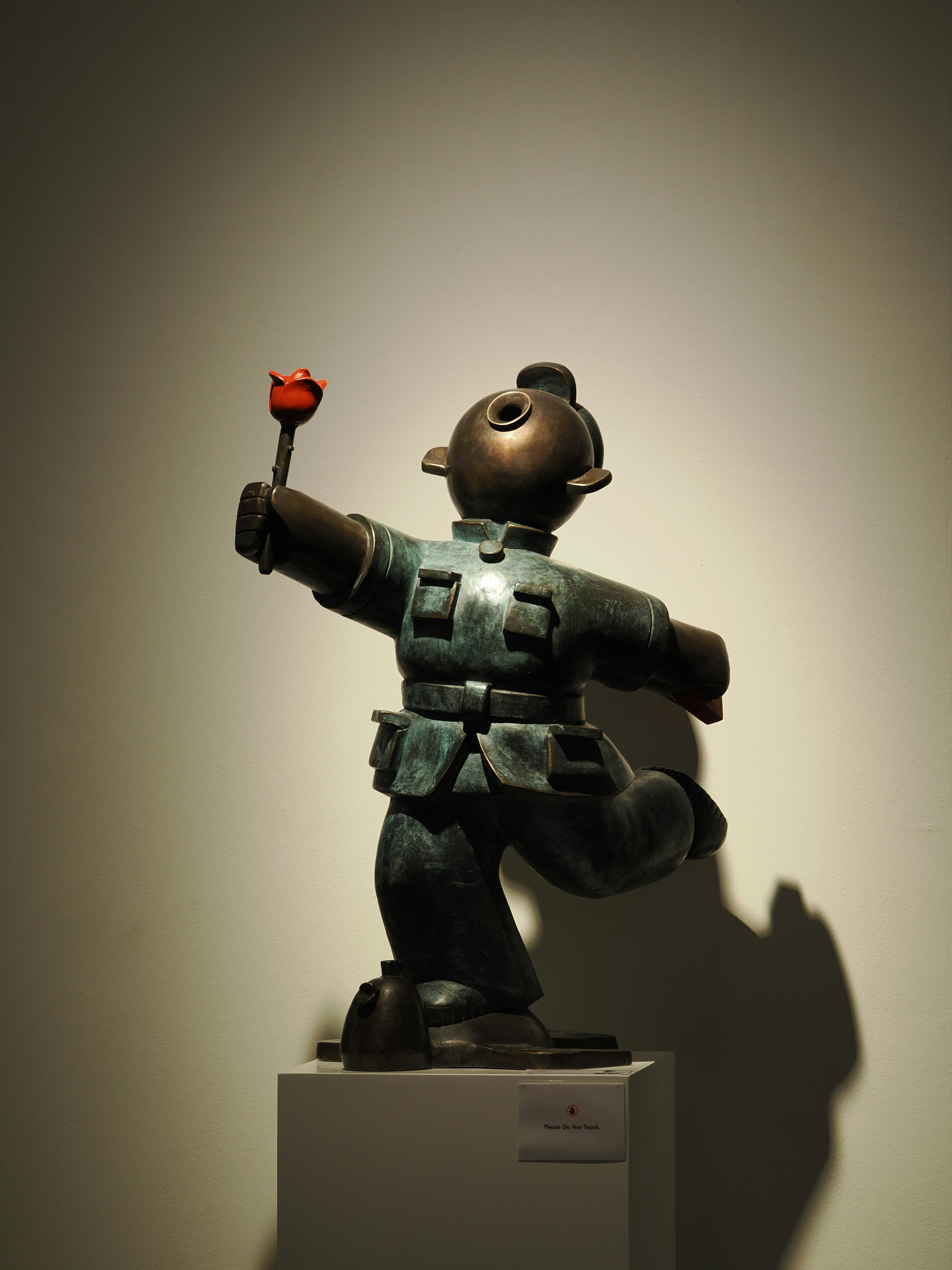 Bronze Sailor: A Tiny Red Rose on a Monumental Arm