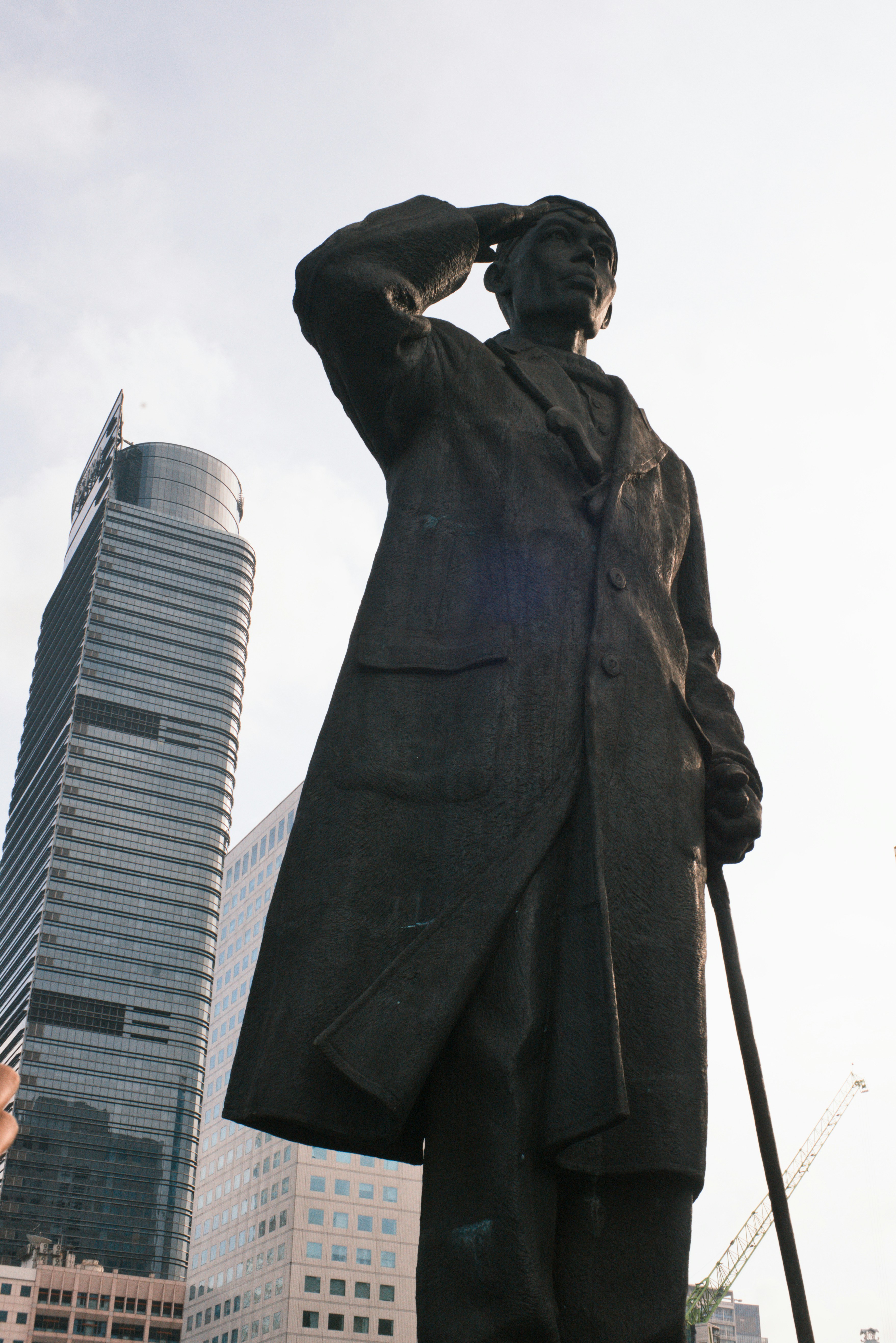Tall Sentinel: A Statue Overlooking a Modern Skyline