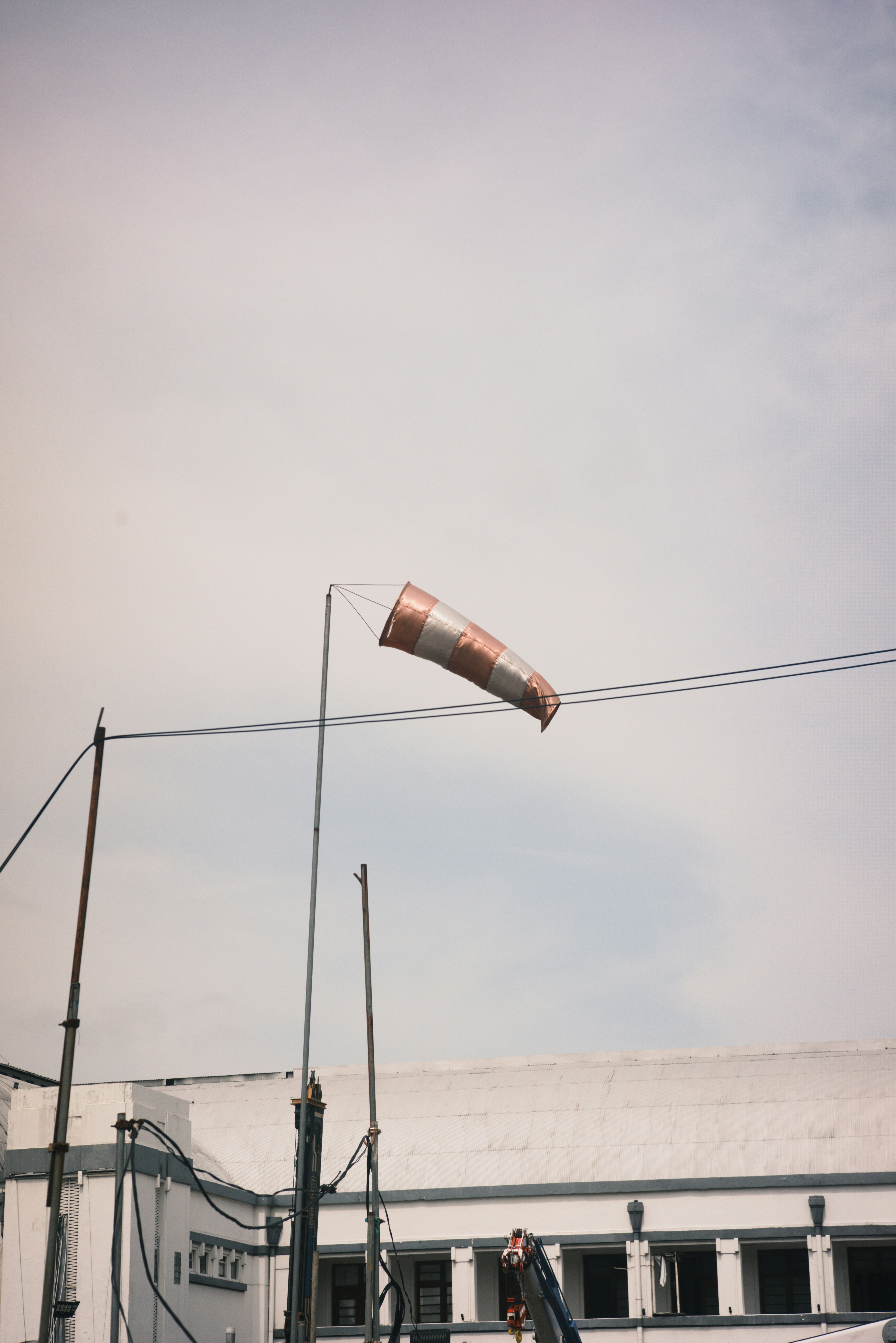 Rust Ribbon in the Sky: A Wind-Swept Wind-Flag over an Industrial Roof