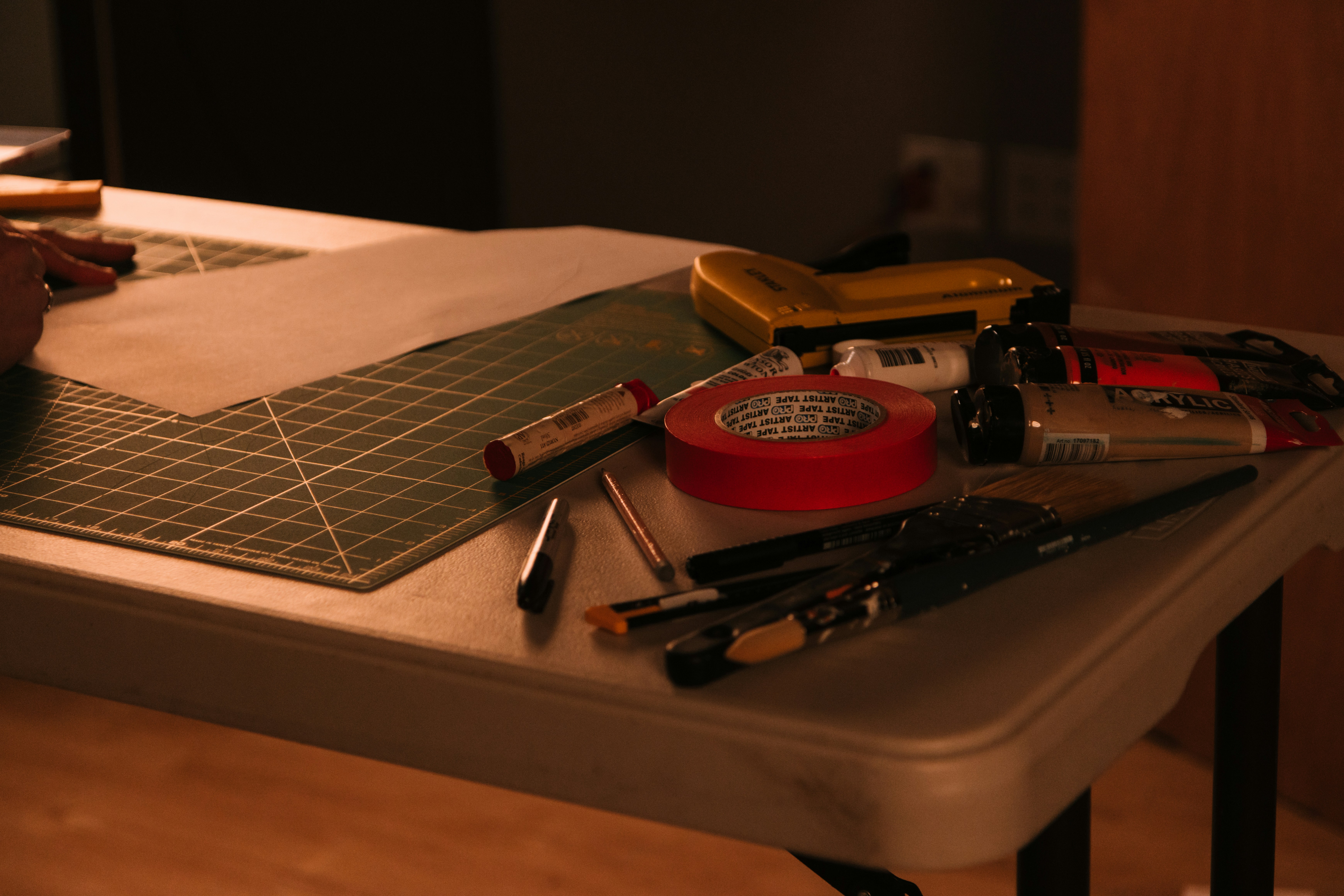 Shadowed Craft Table: Tools and Tape Bathed in Low Light