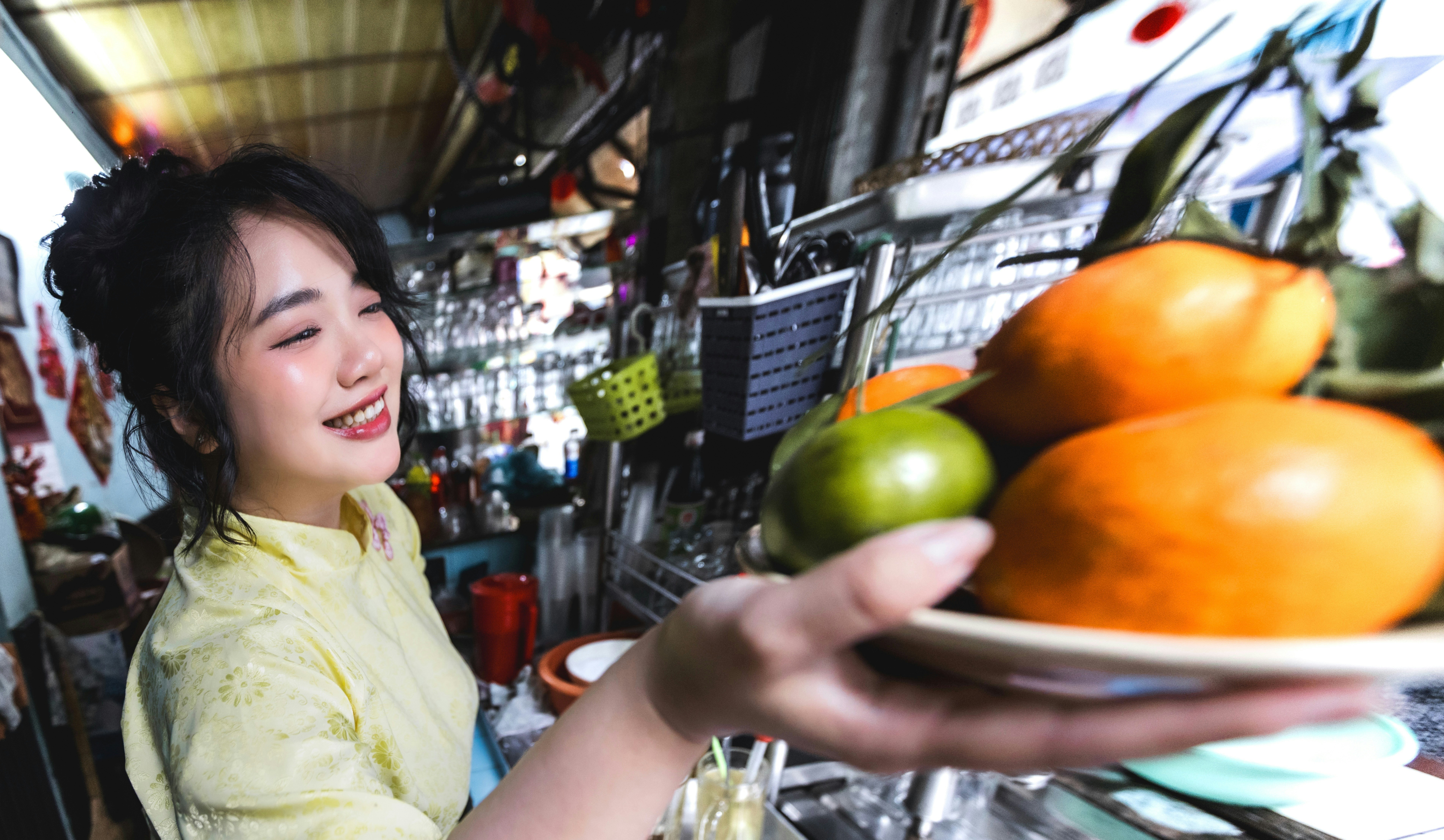 Smiling vendor offering a bright fruit platter in a bustling market