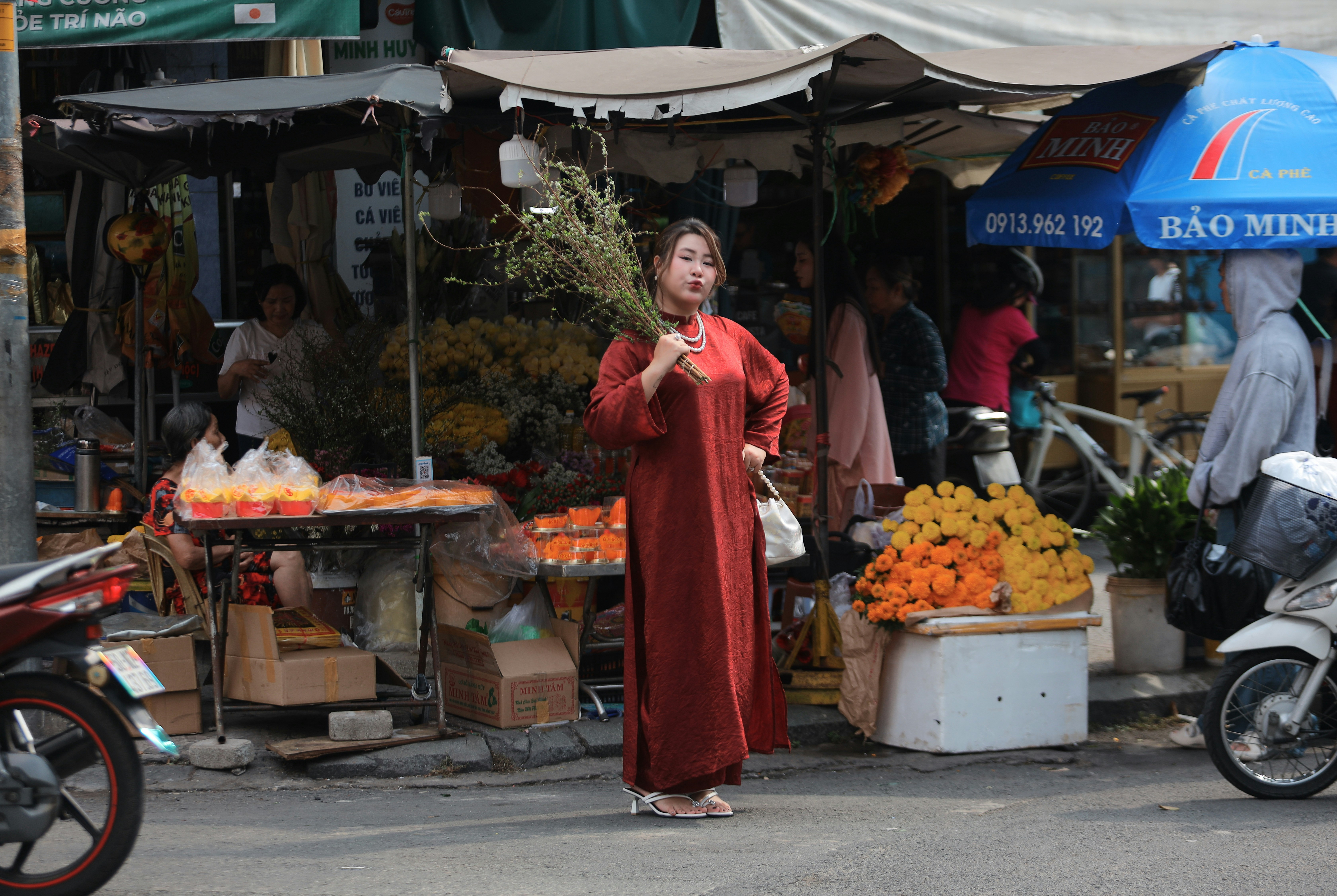 Red dress in a bustling market: a quiet moment among bright blooms