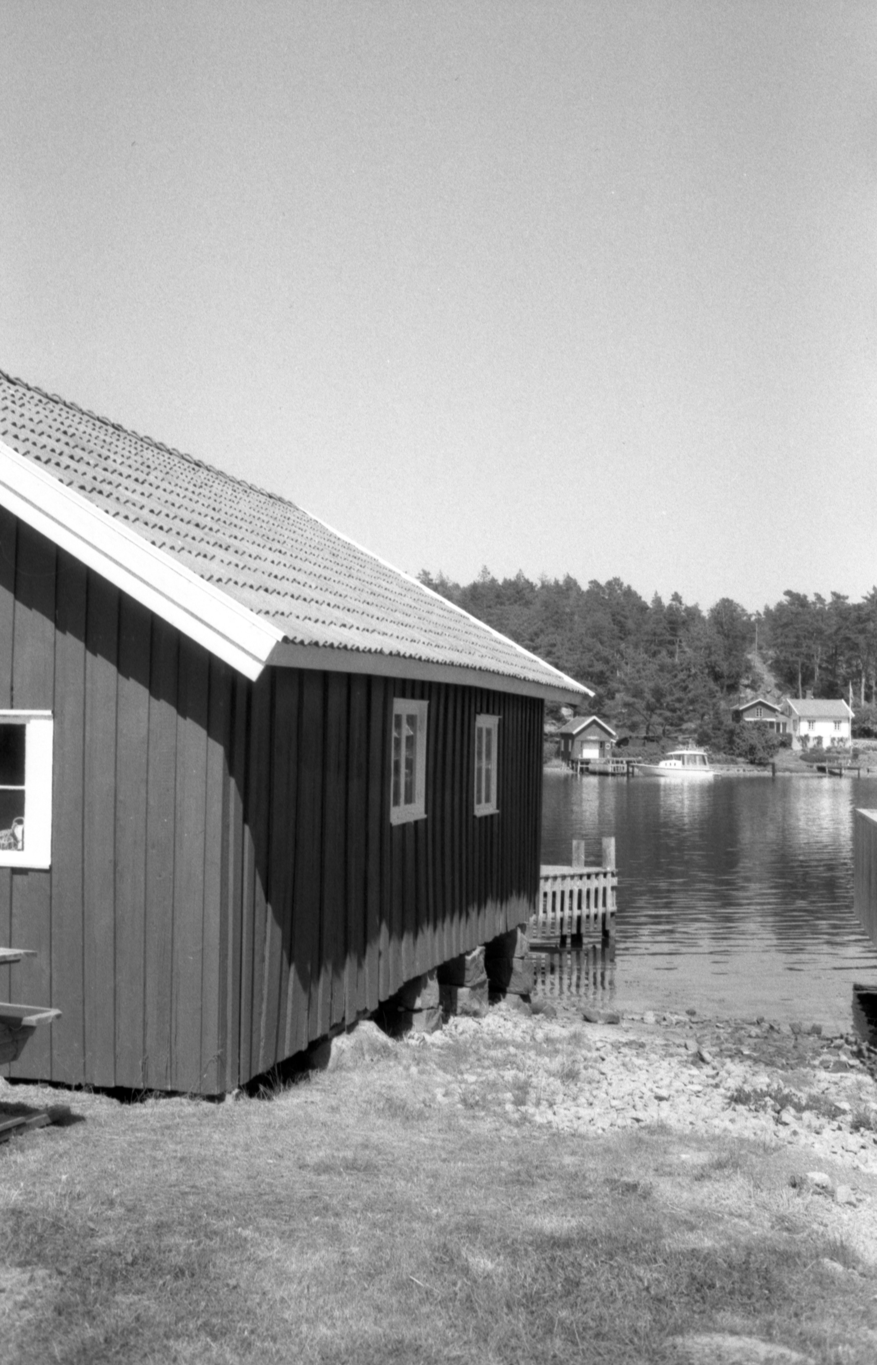 Wooden boathouse on the water with trees in background.