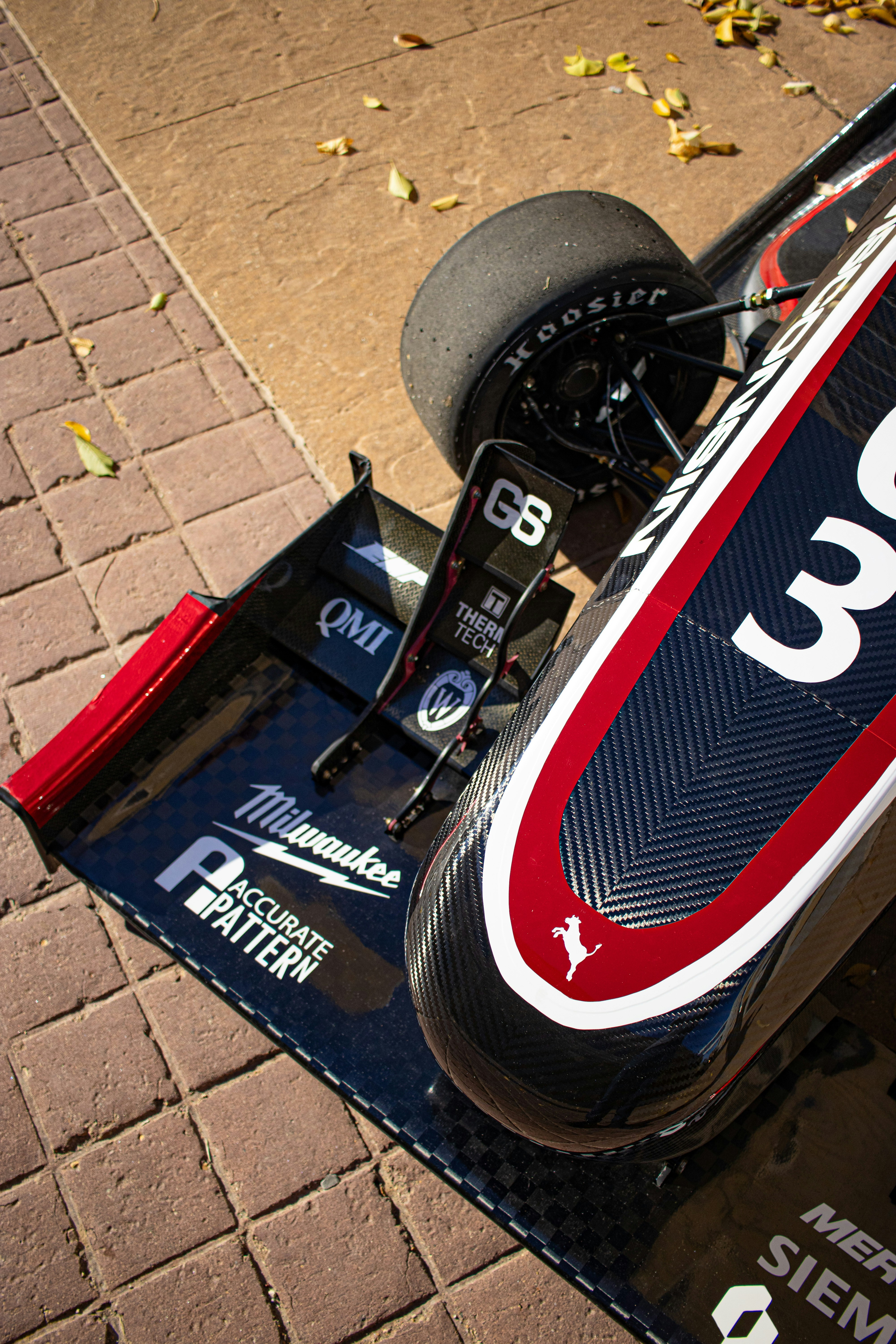 Close-up of a numbered racing board with bold branding and a large wheel on a textured surface, highlighting the streamlined deck and sponsor logos.