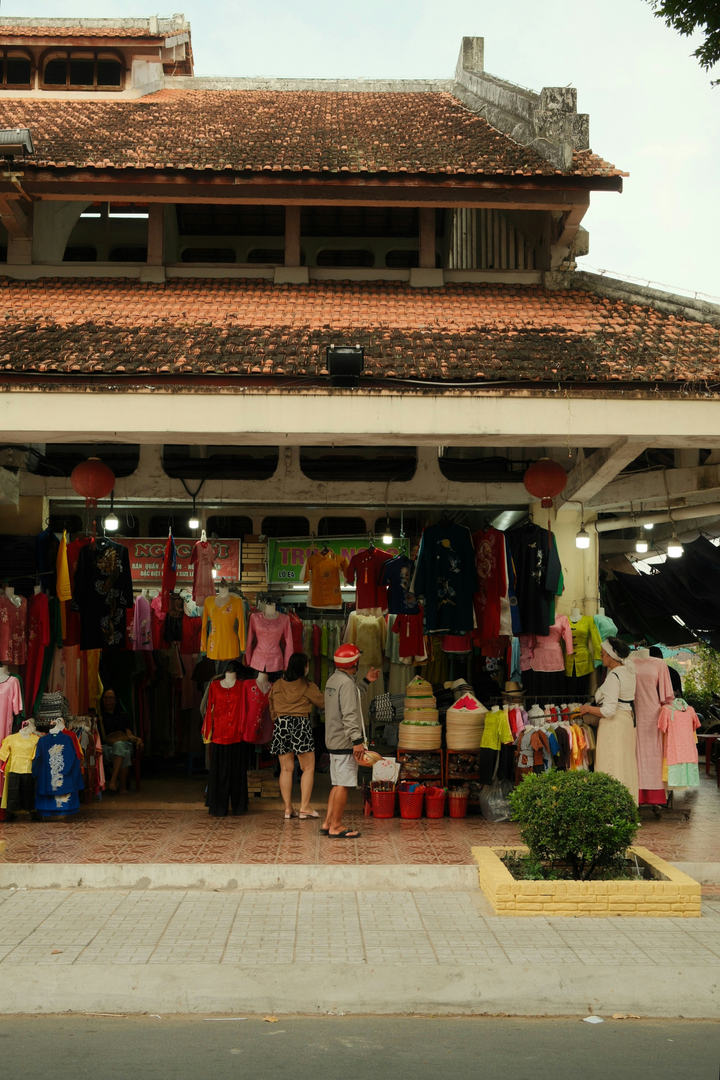Marketfront: Colorful Clothing Street Scene Under a Reddish Roof