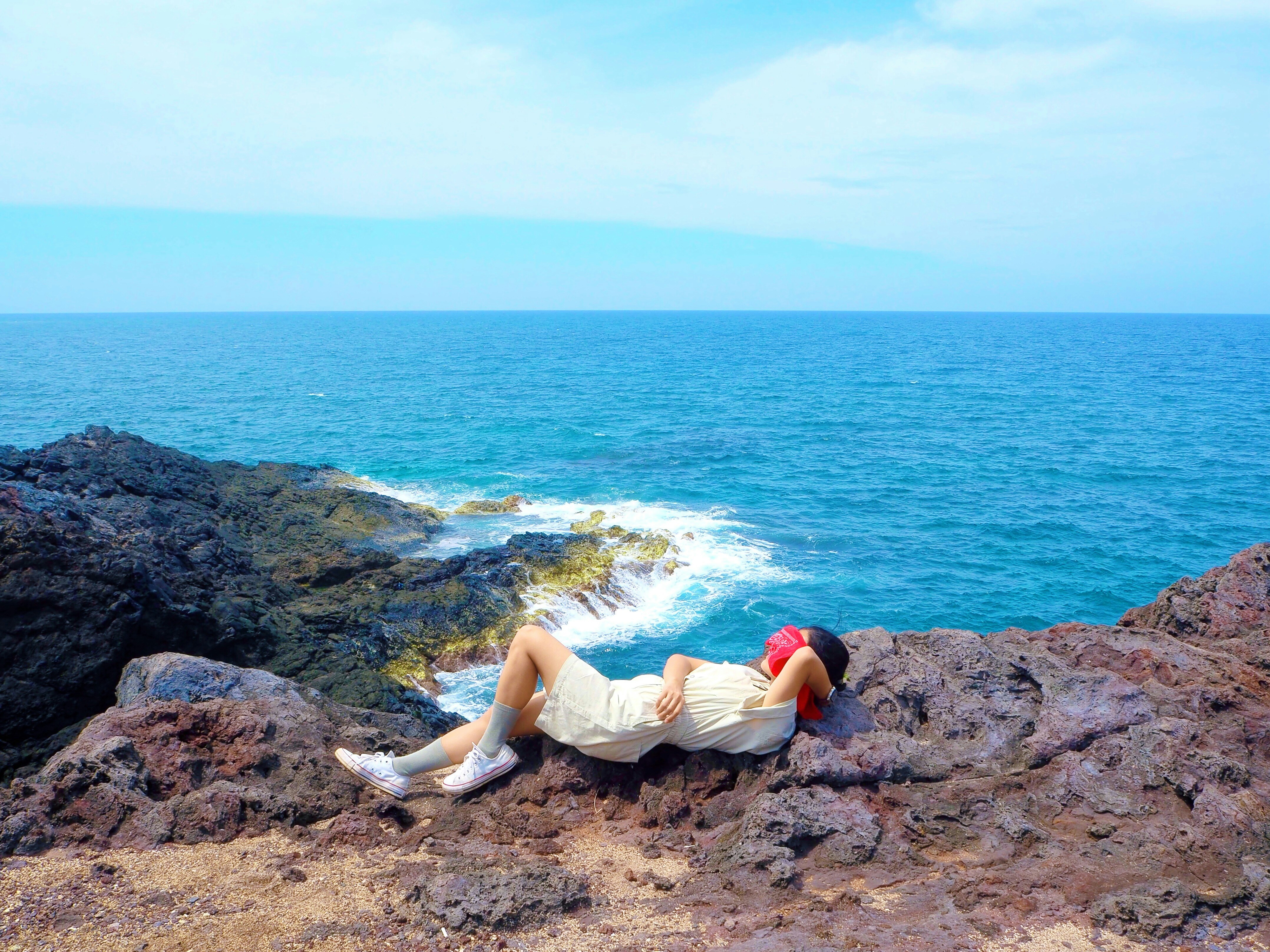 Relaxing on volcanic cliffs with turquoise sea under a clear sky