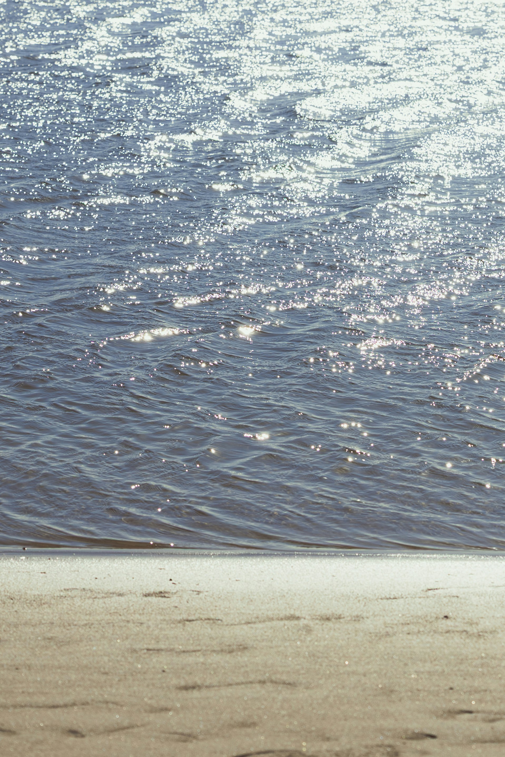 Glittering Seashore: Sunlit Waves at the Waterline