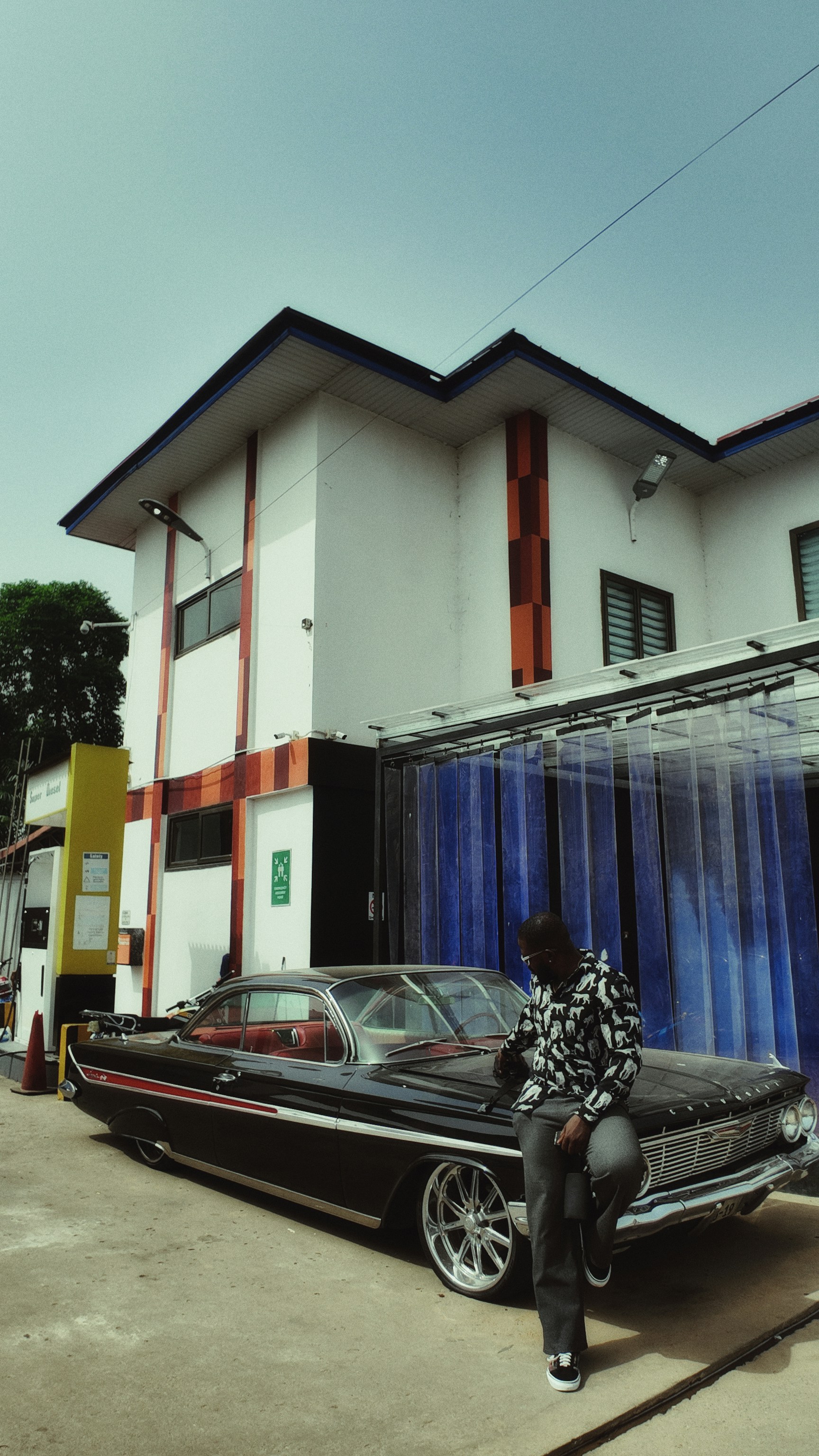 Man leaning on a classic black car outside building