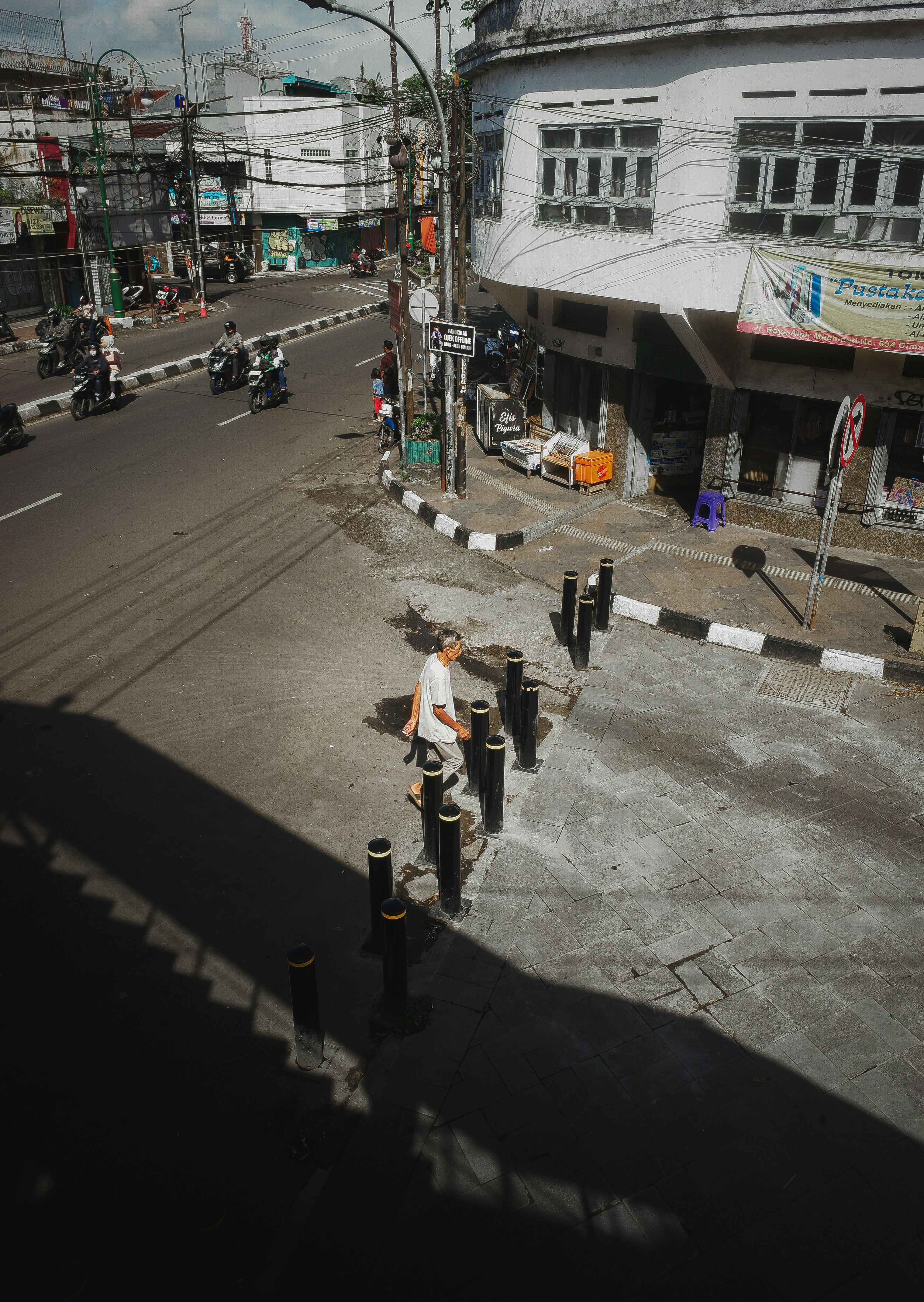 Person sitting on bollards on a city street.
