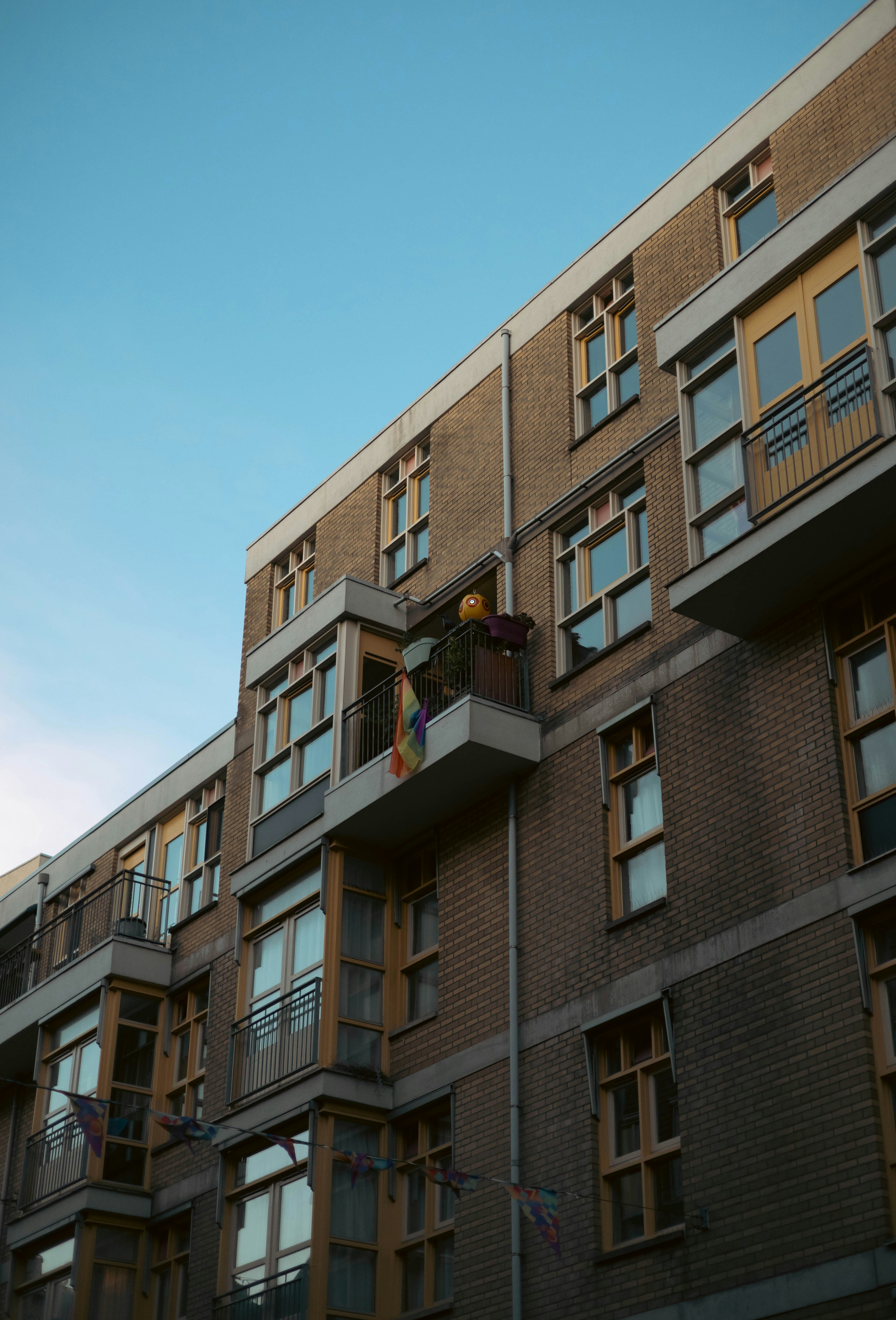 Balcony Flag and Brick Facade Under a Quiet Blue Sky