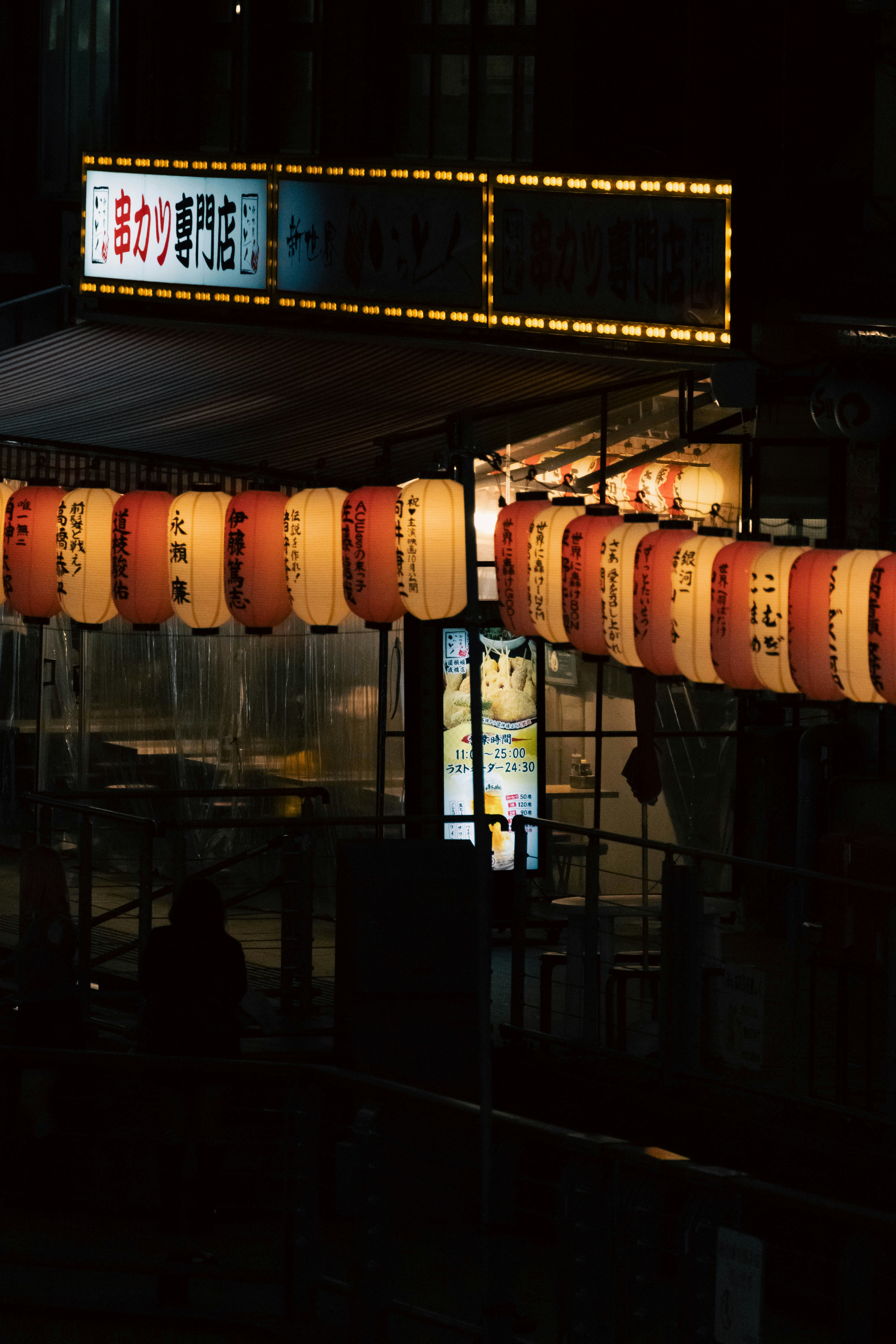 Row of glowing lanterns over a quiet nighttime street scene
