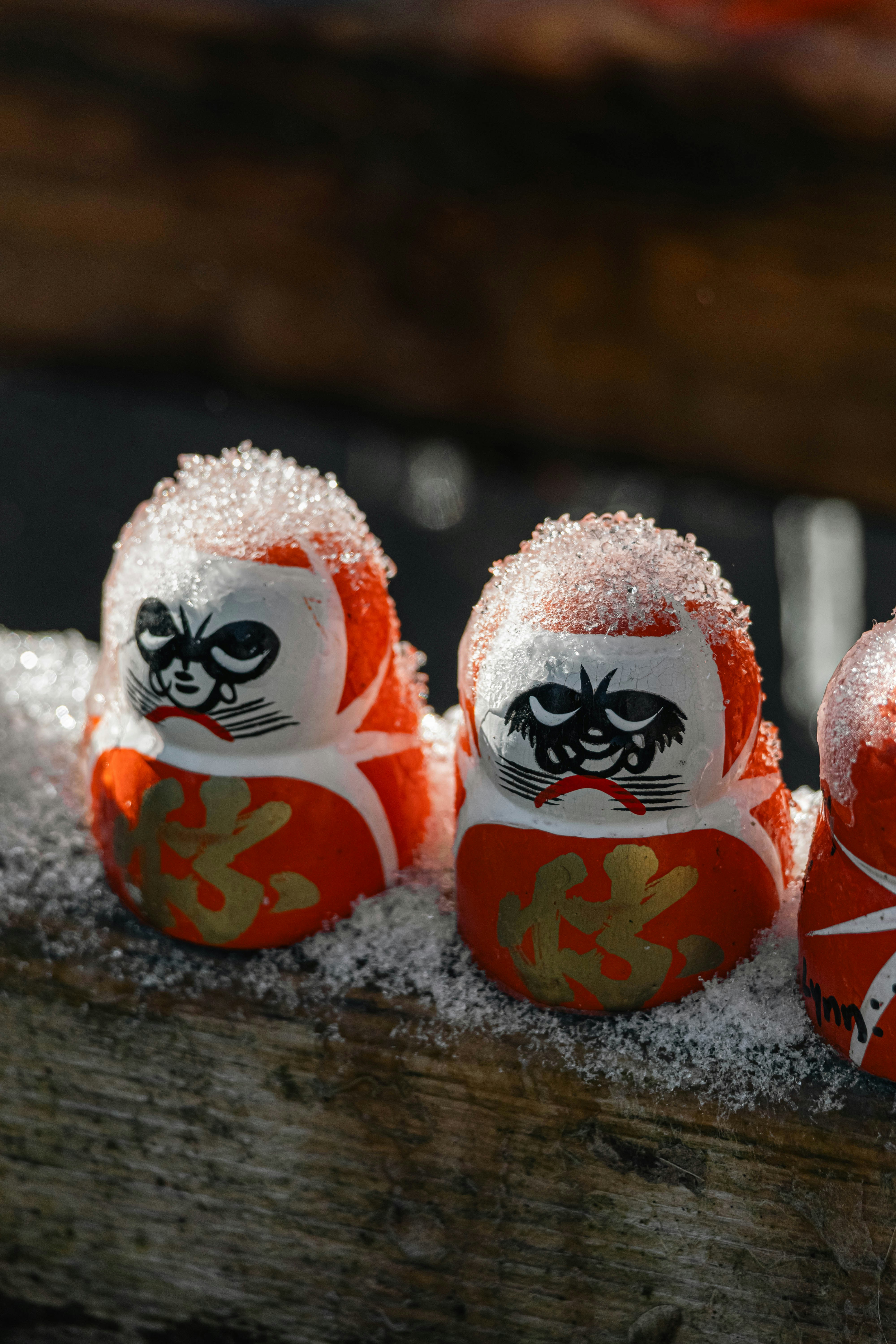Frozen Daruma: Red Daruma Faces on a Icy Wood Slab