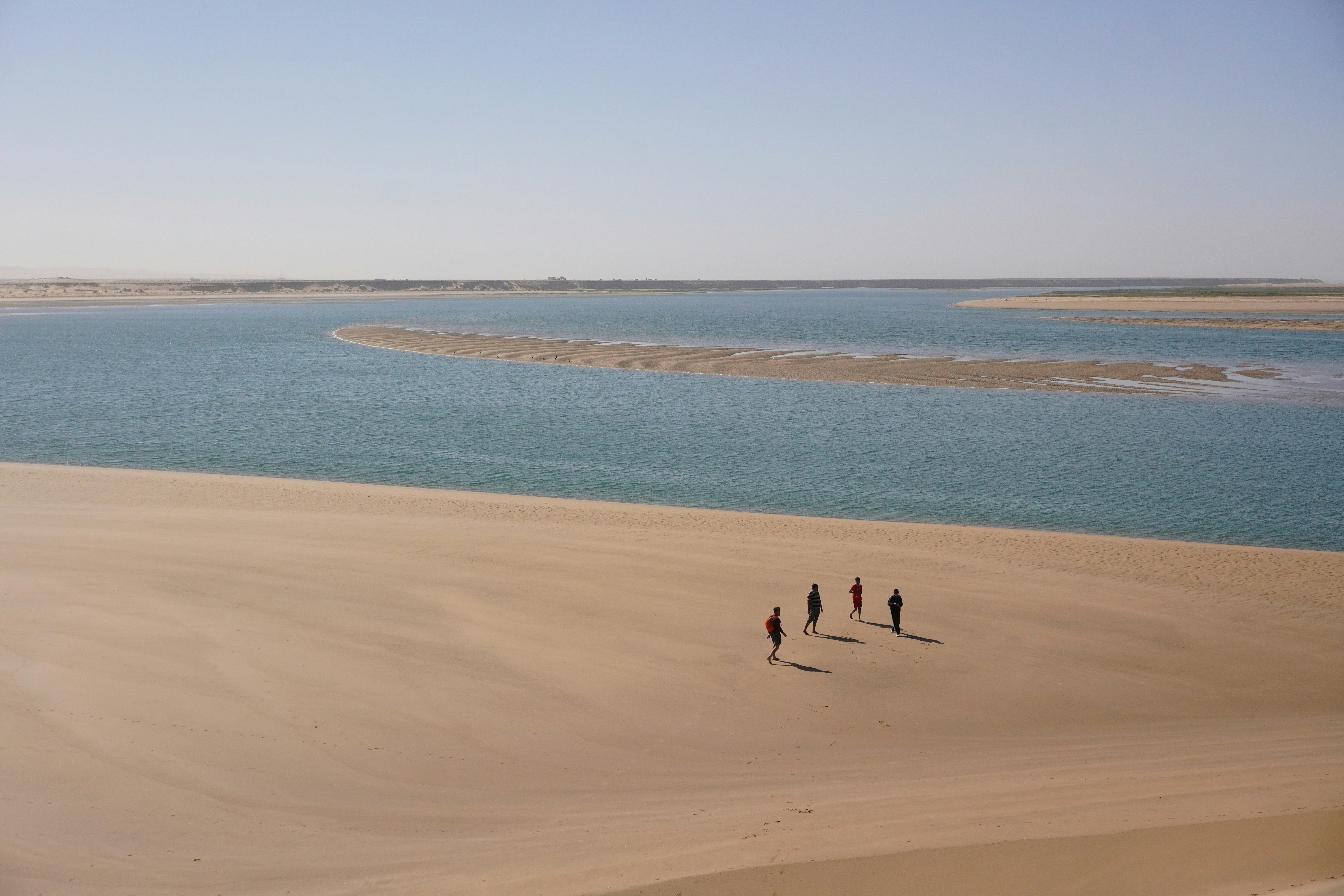 Shadowed Figures on a Curving Shoreline