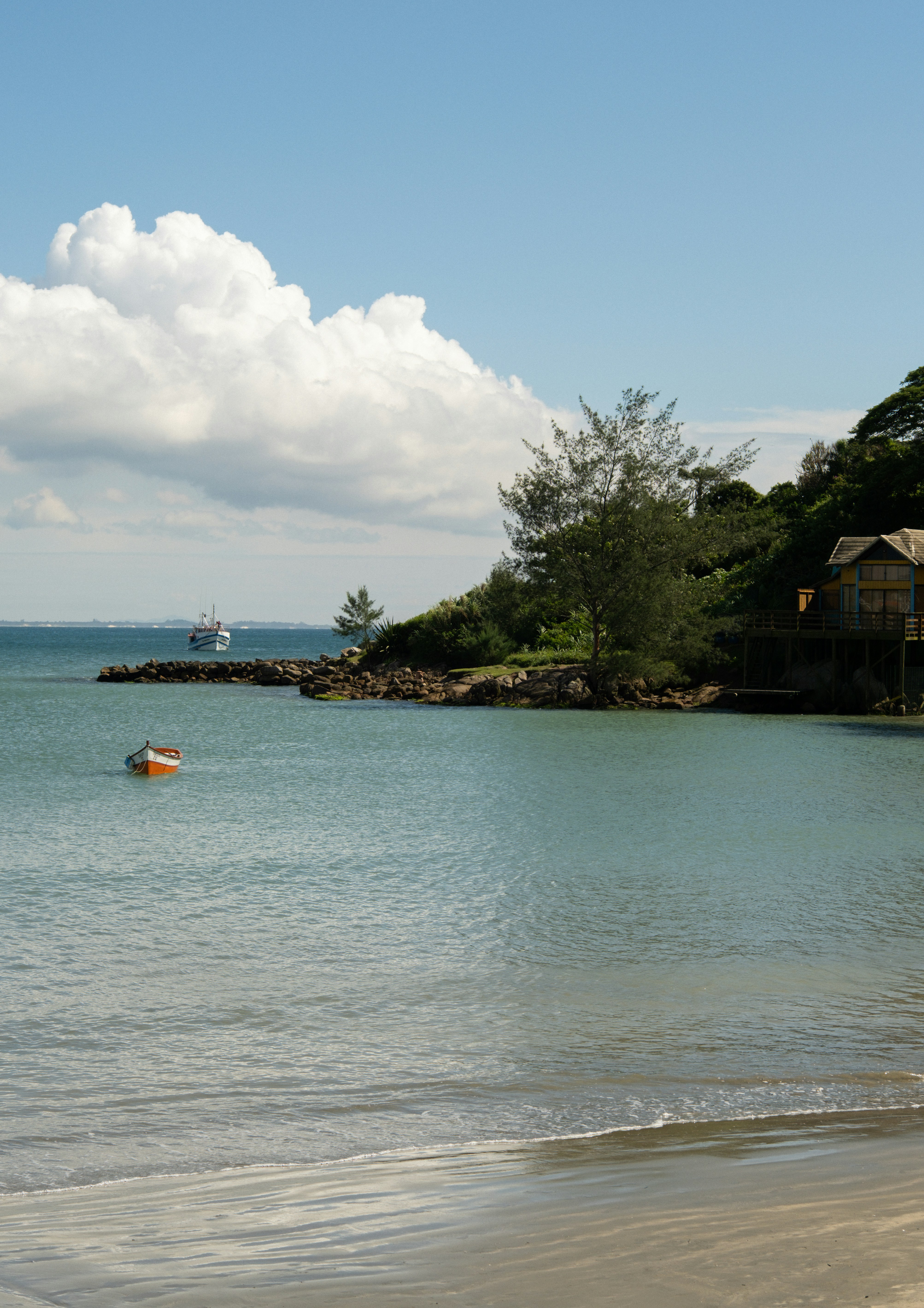 Quiet cove at low tide with a lone orange boat and seaside cottages