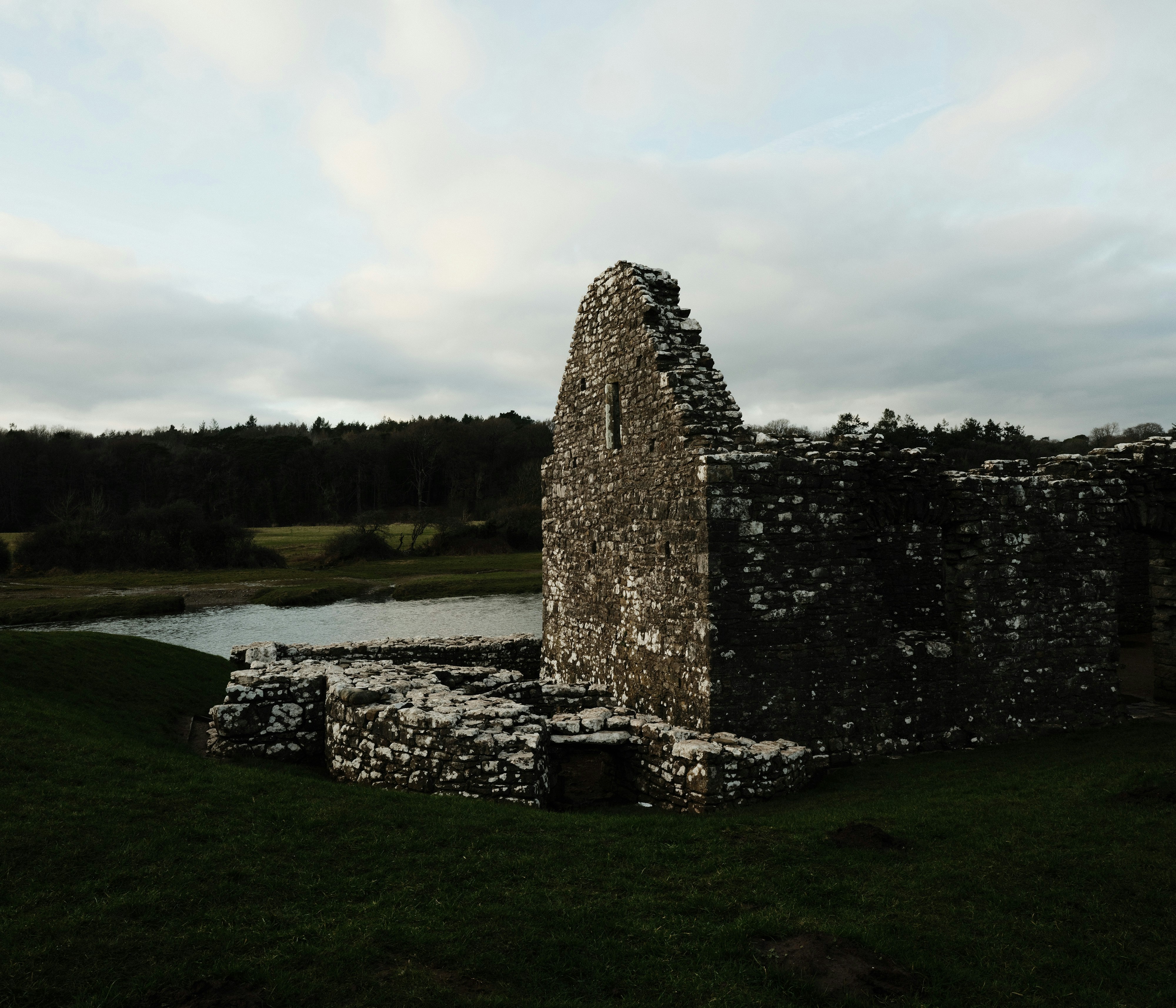 Ancient stone ruins on a grassy hill by a lake