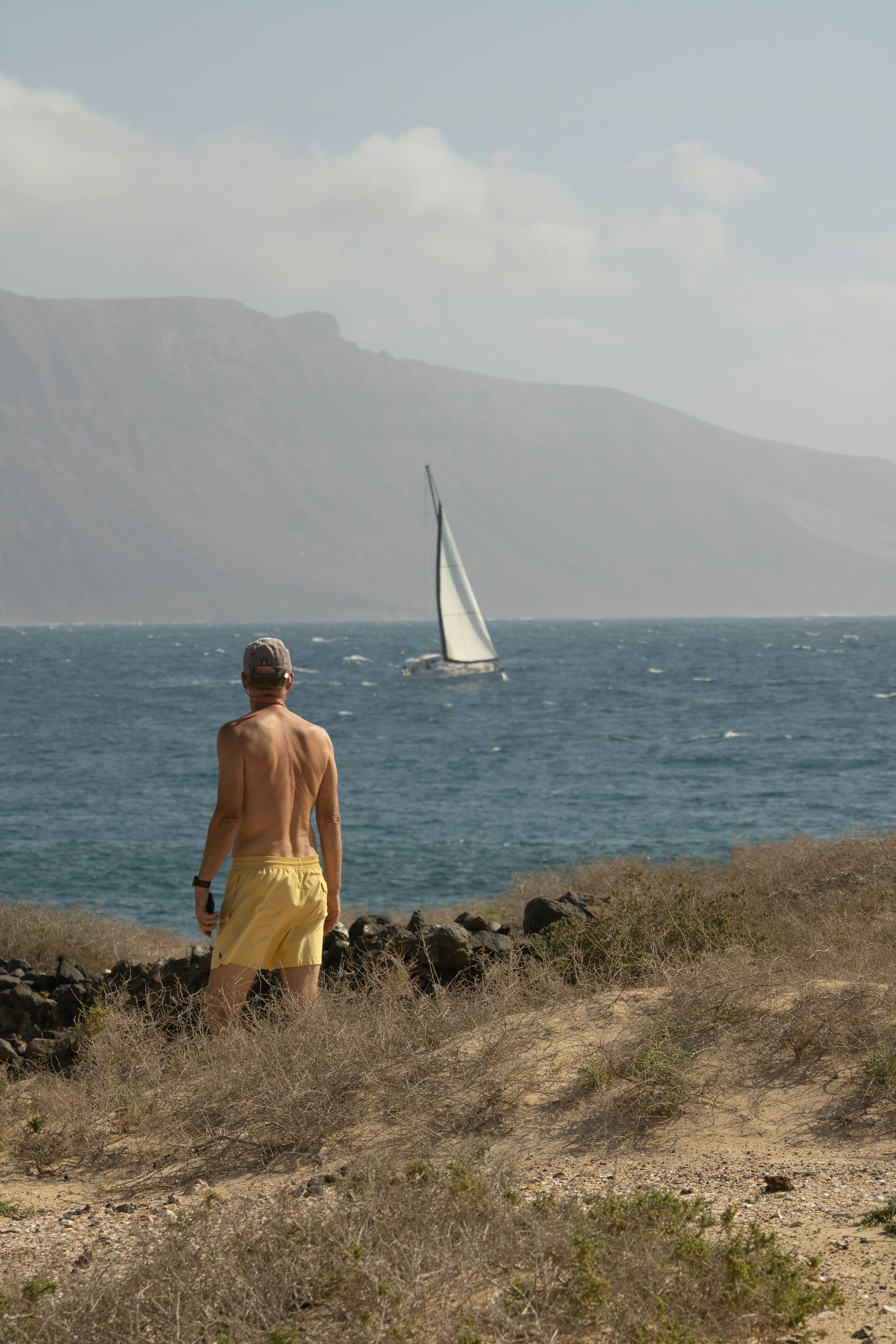 Shoreline Silhouette: Sailboat and Seaside Wanderer
