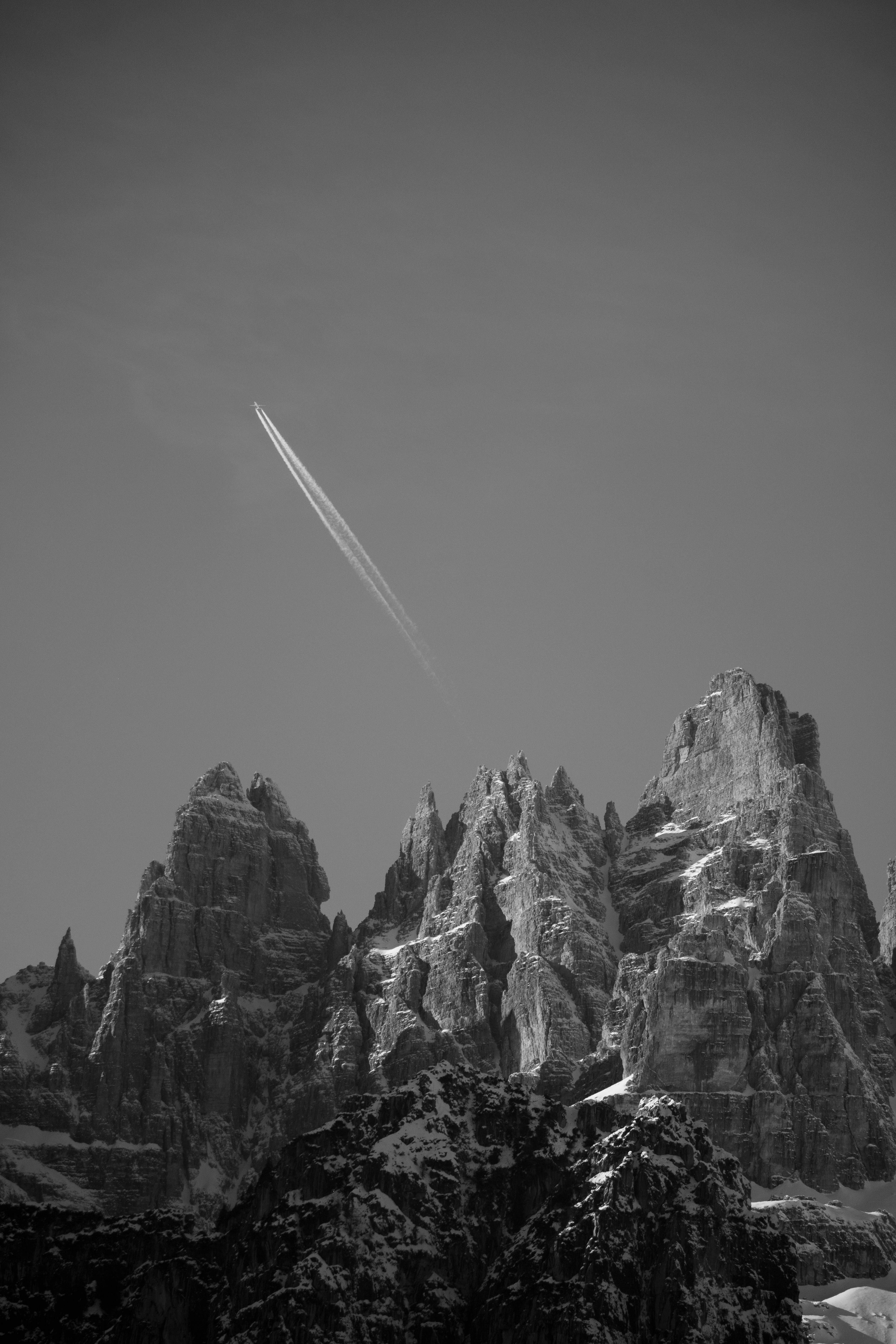 Jet Stream Over Jagged Peaks: A Monochrome Ascent