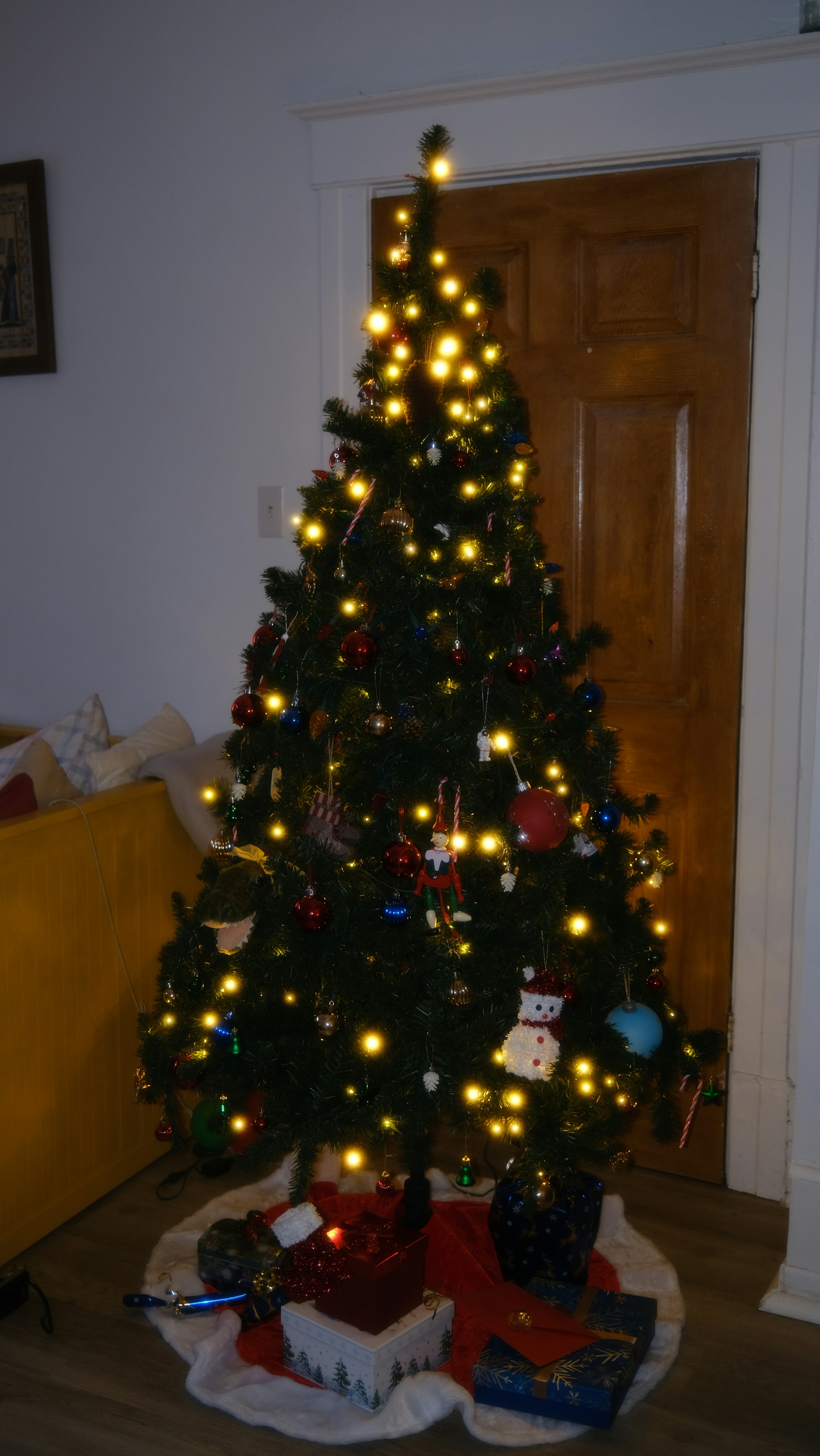 Twinkling Christmas Tree Standing Guard by the Wooden Door