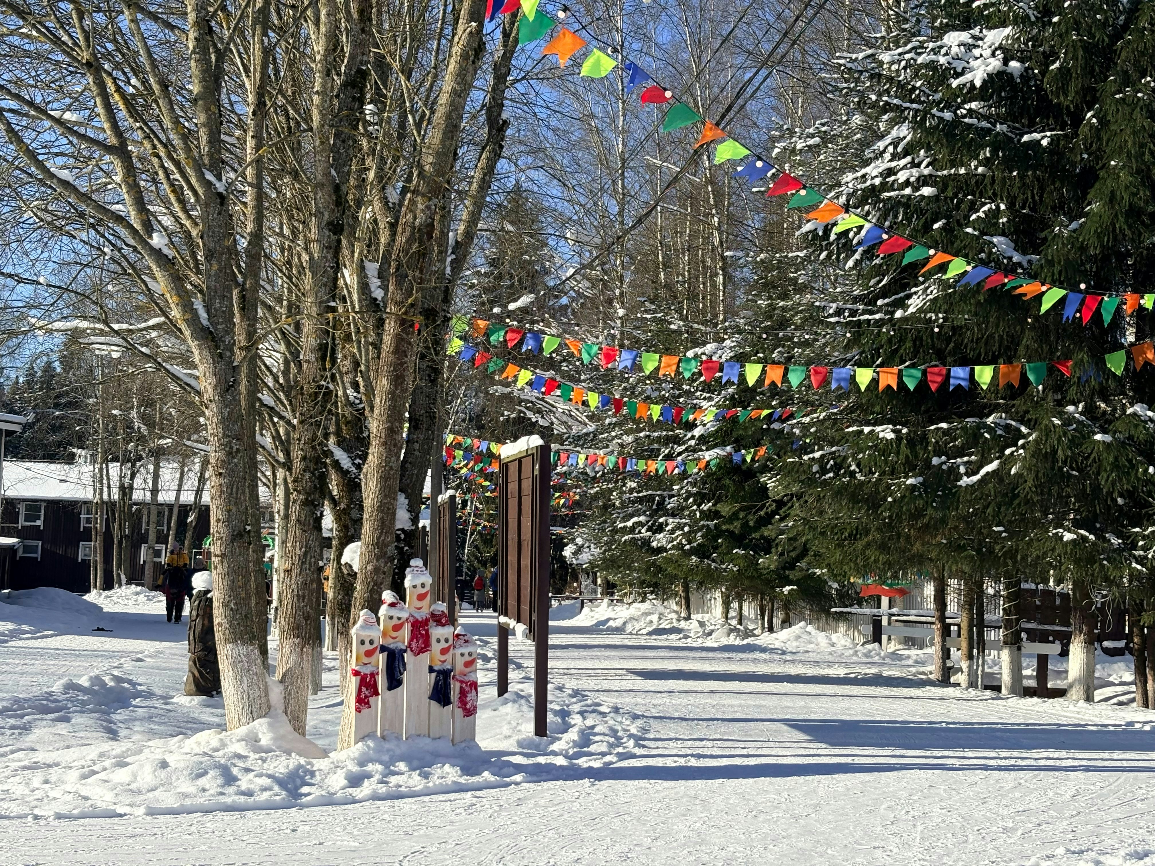 Snowy park with colorful pennant arches framing a playful snowman display