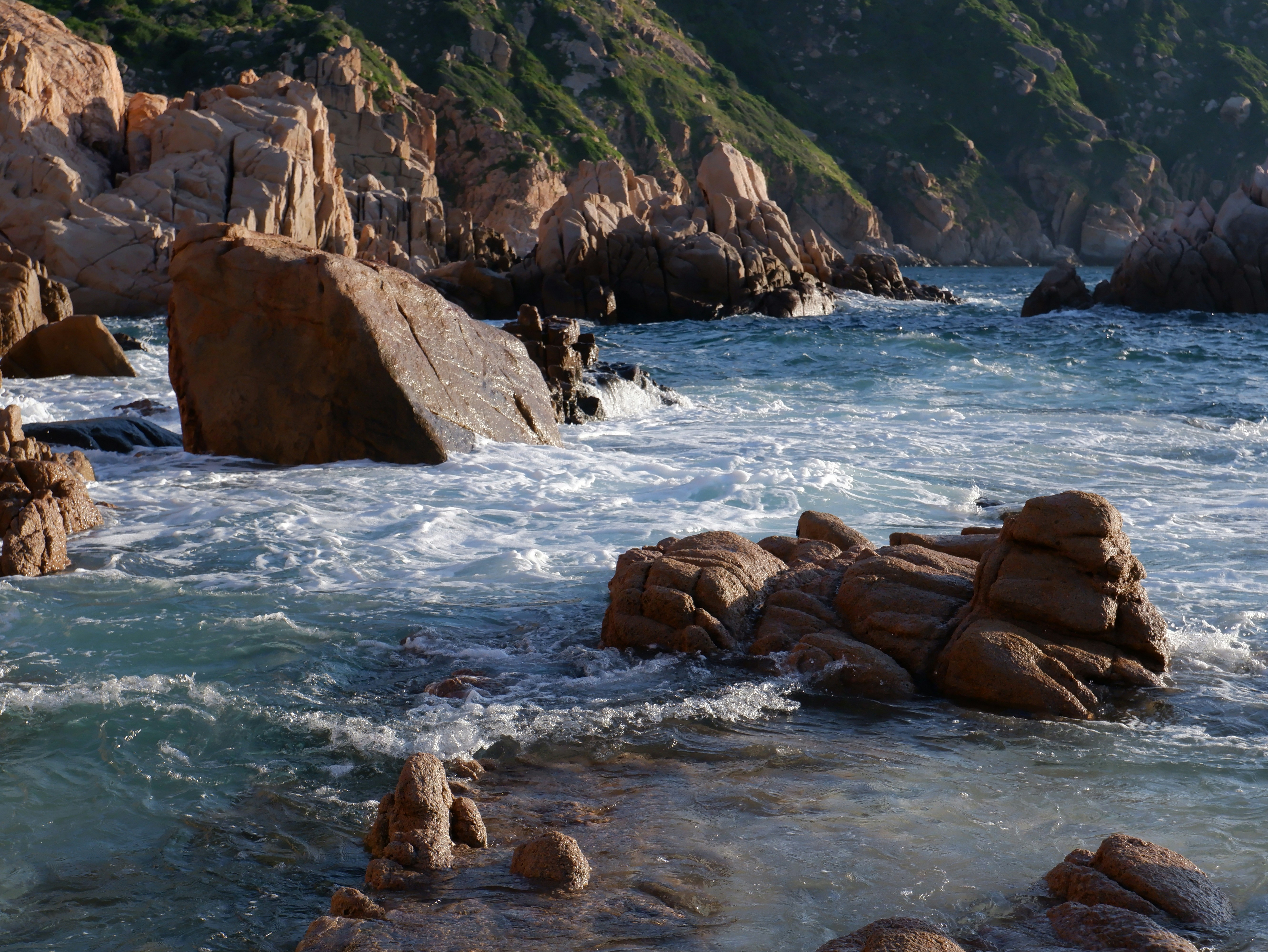 Coastal Boulders and Turbulent Tide Against a Rugged Cliffline