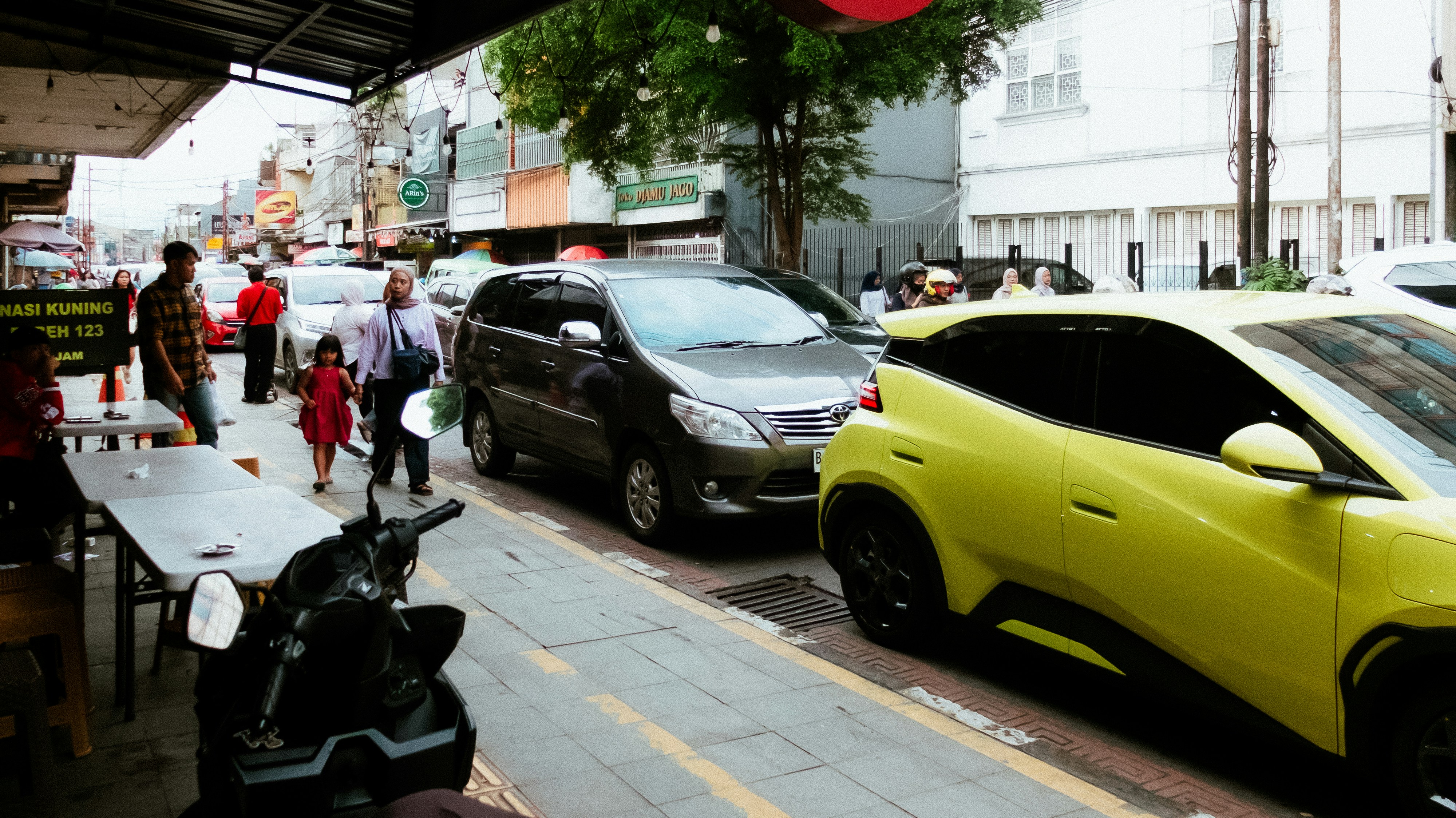 Yellow SUV Leaning Into the Street, Pedestrians Pausing by the Market