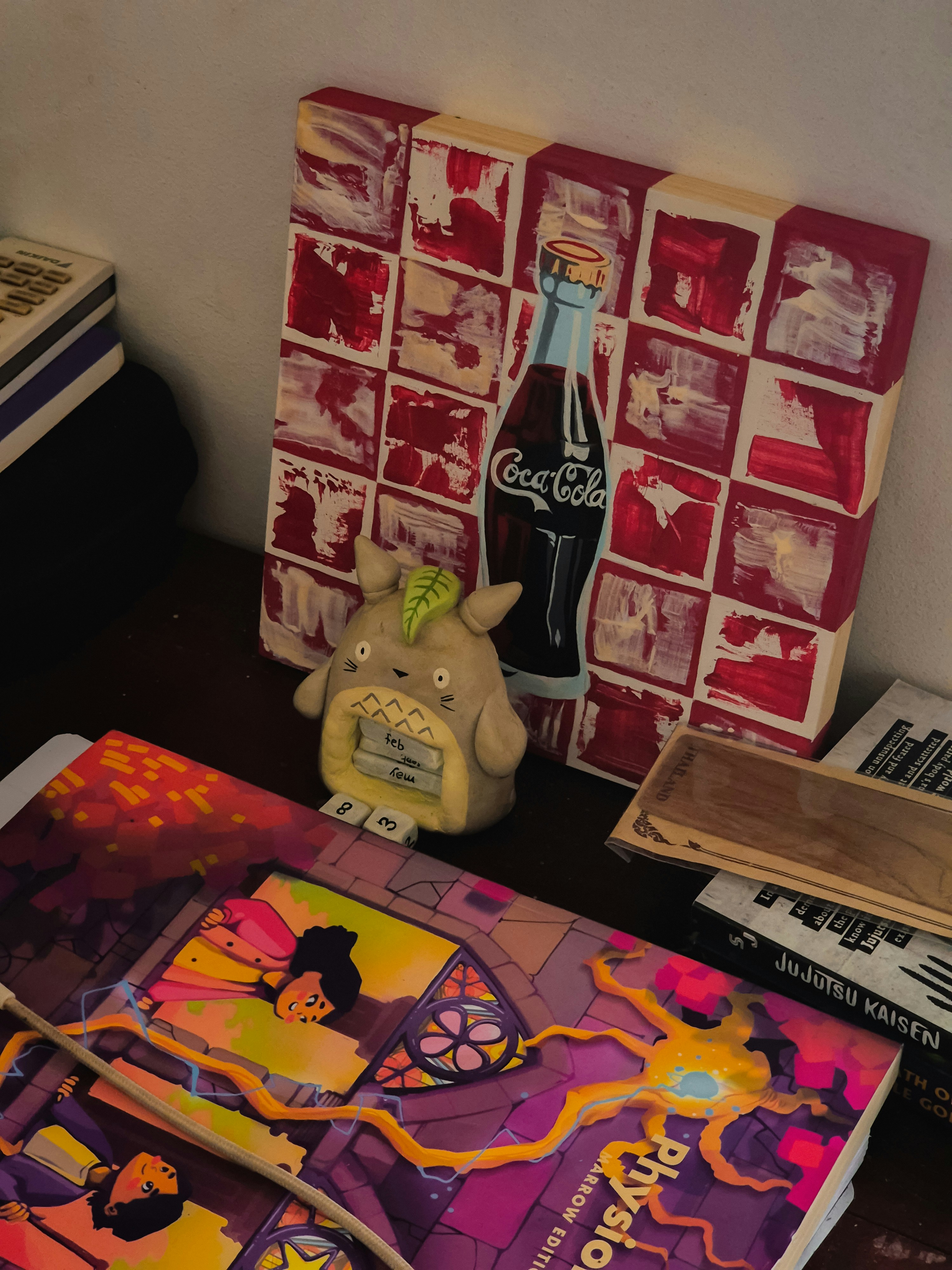 Coca-Cola canvas and colorful game-book clutter on a cluttered desk